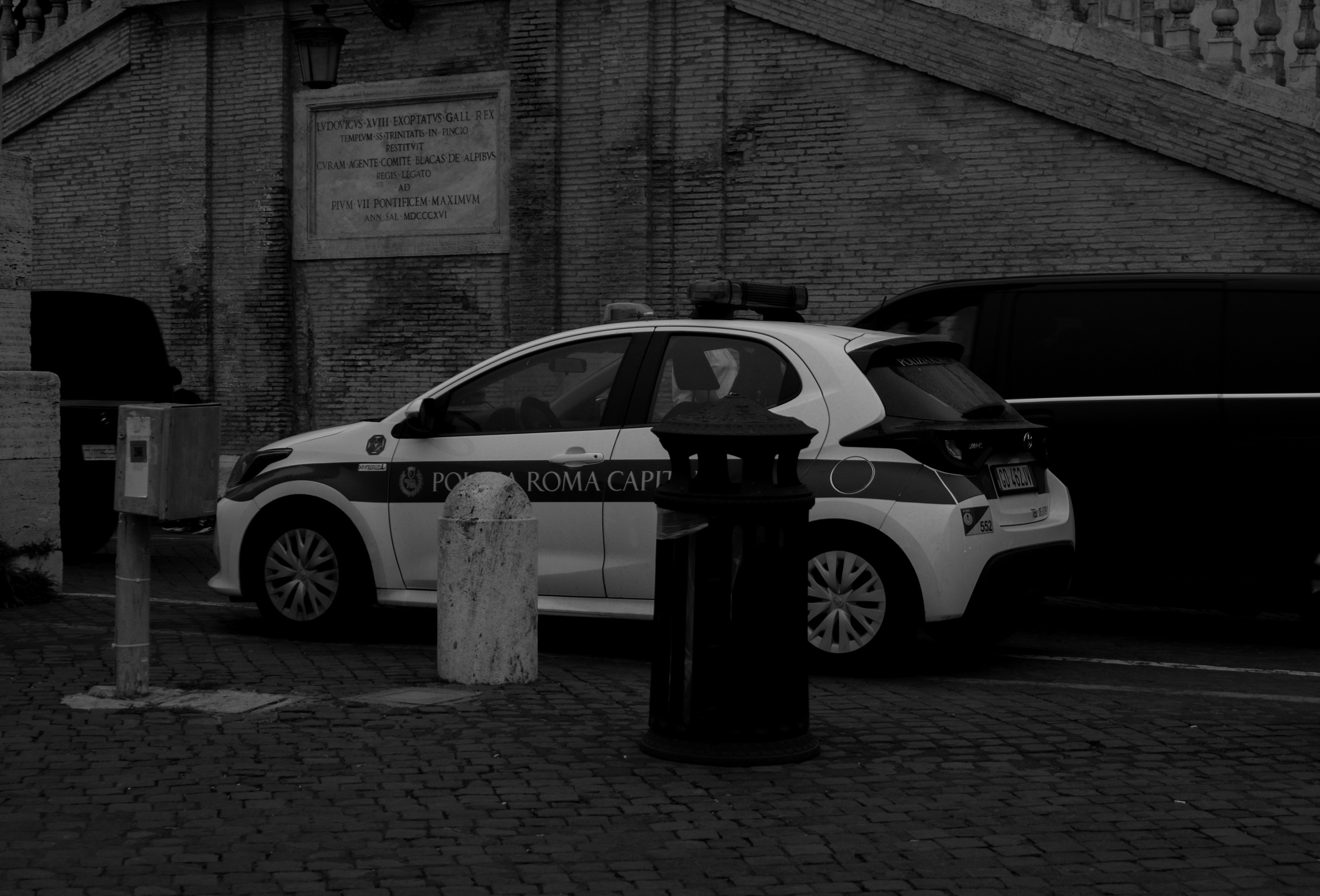 Monochrome Patrol: Roma Capitale Car Anchoring a Quiet Brick Courtyard