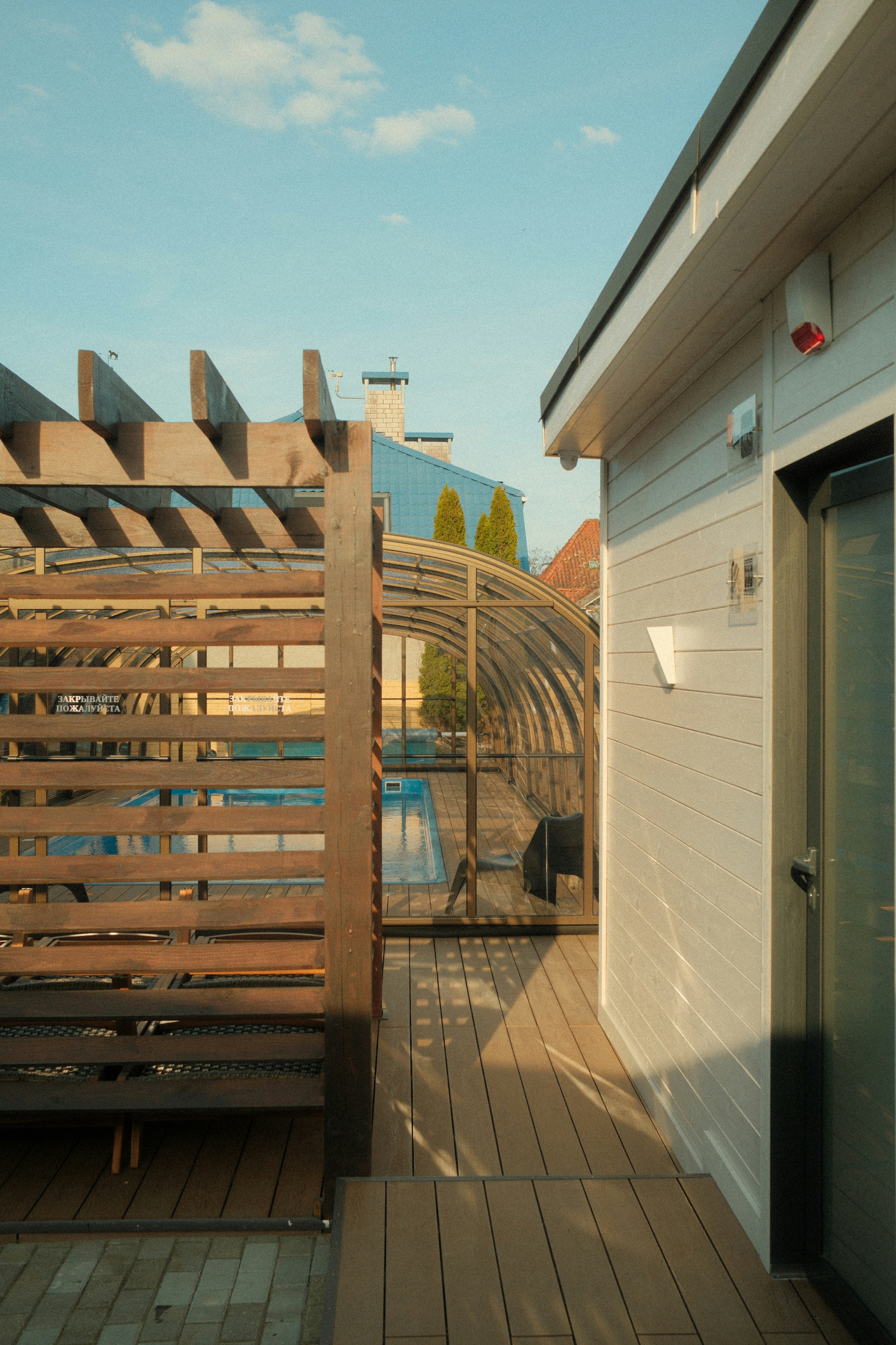 Sunlit Deck Corridor Framing a Curved Glass Oasis