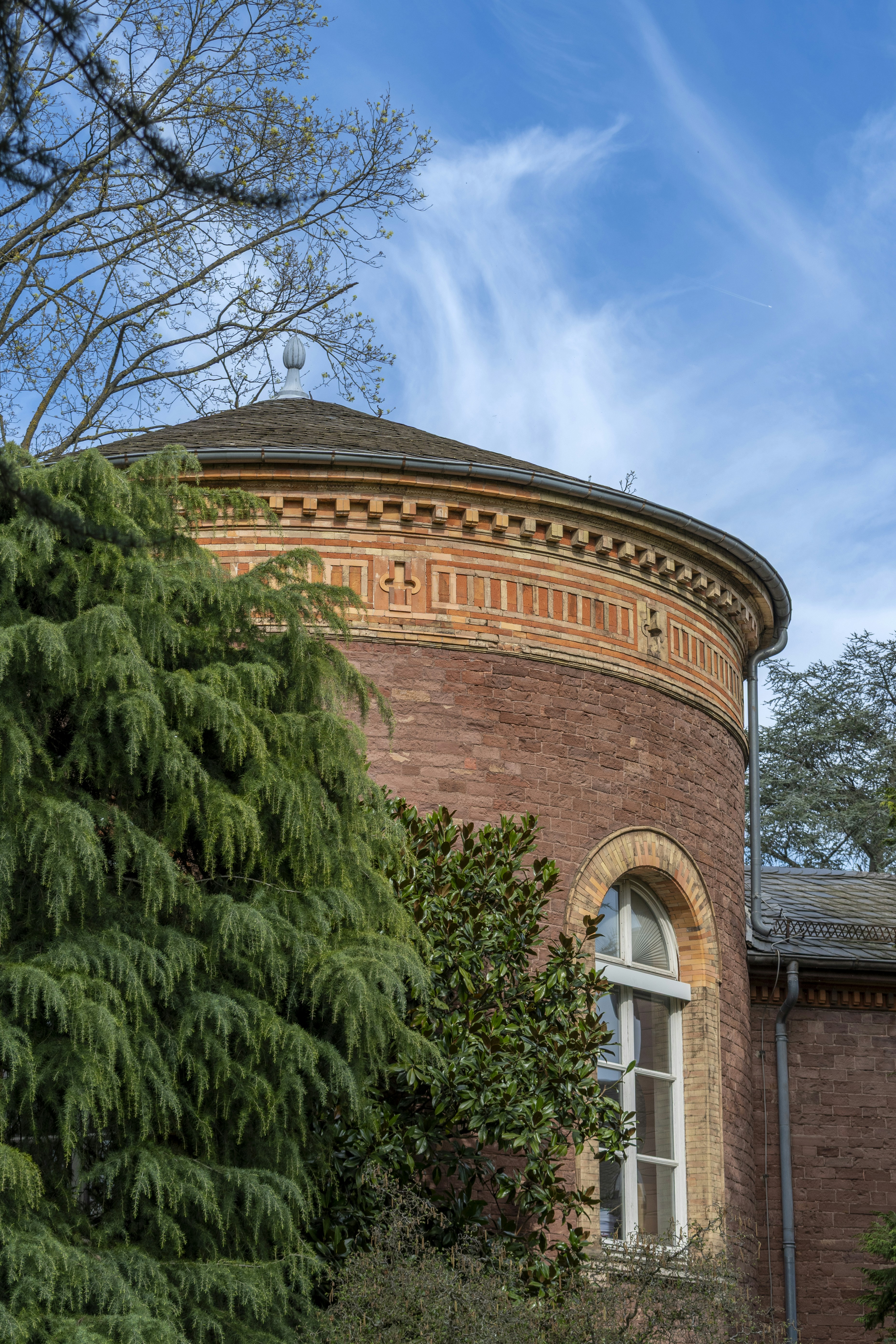 Brick Roundhouse Emerges From a Tangle of Greenery Under a Clear Sky