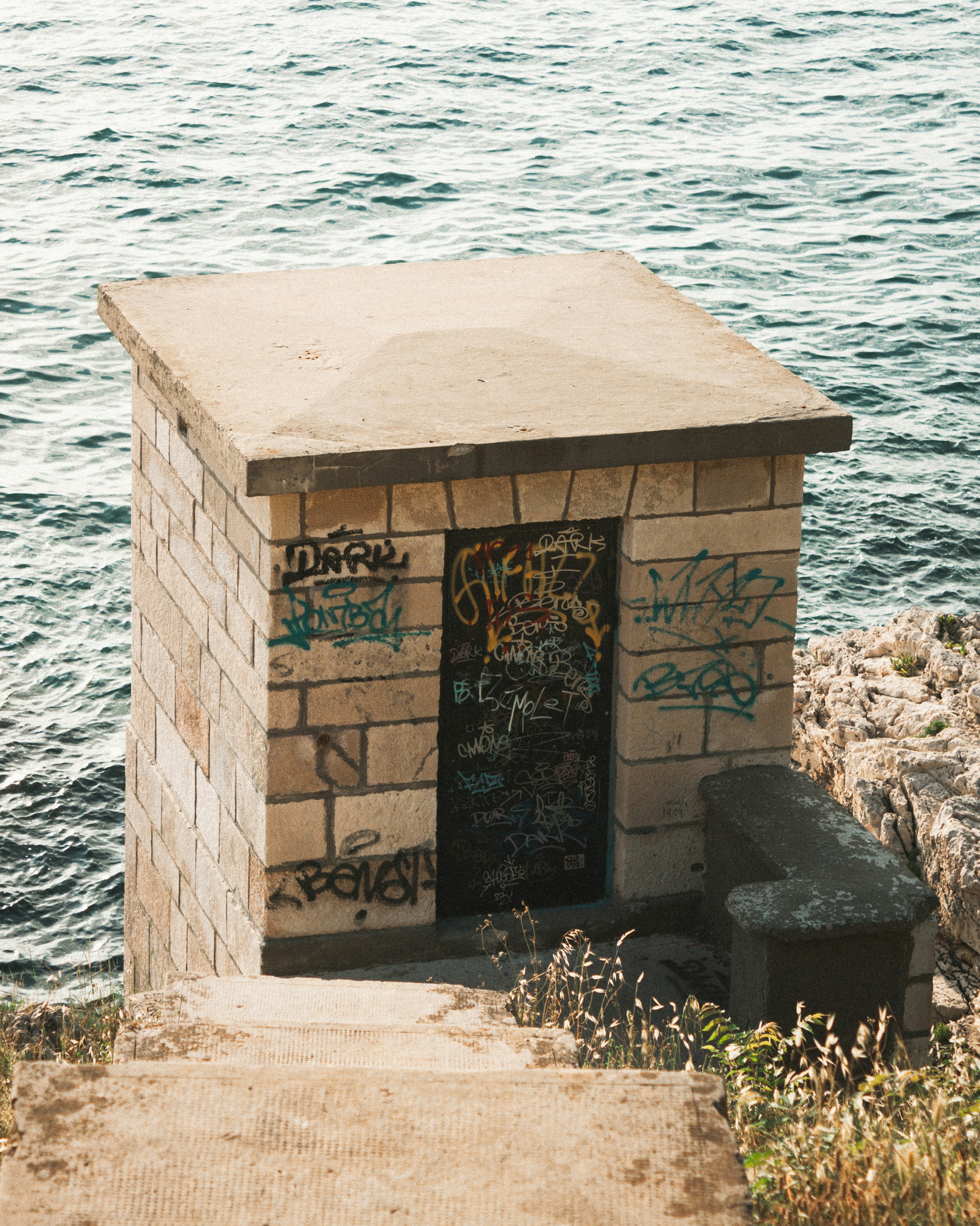 Seaside Graffiti Door: A Weathered Stone Shelter Overlooking the Surf