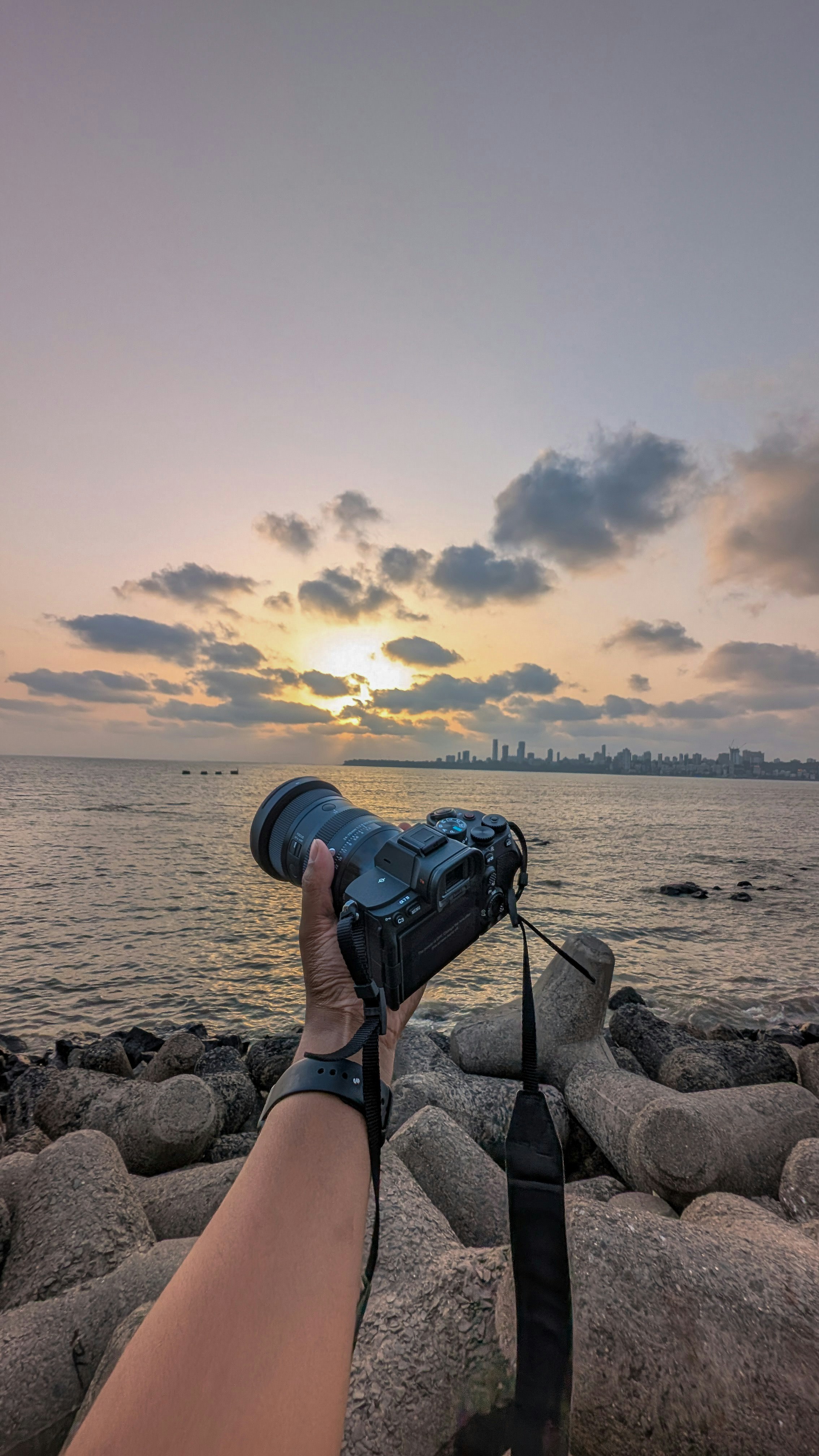 A photographer capturing a sunset over the ocean, with a city skyline in the background. The scene highlights the connection between the artist and nature.