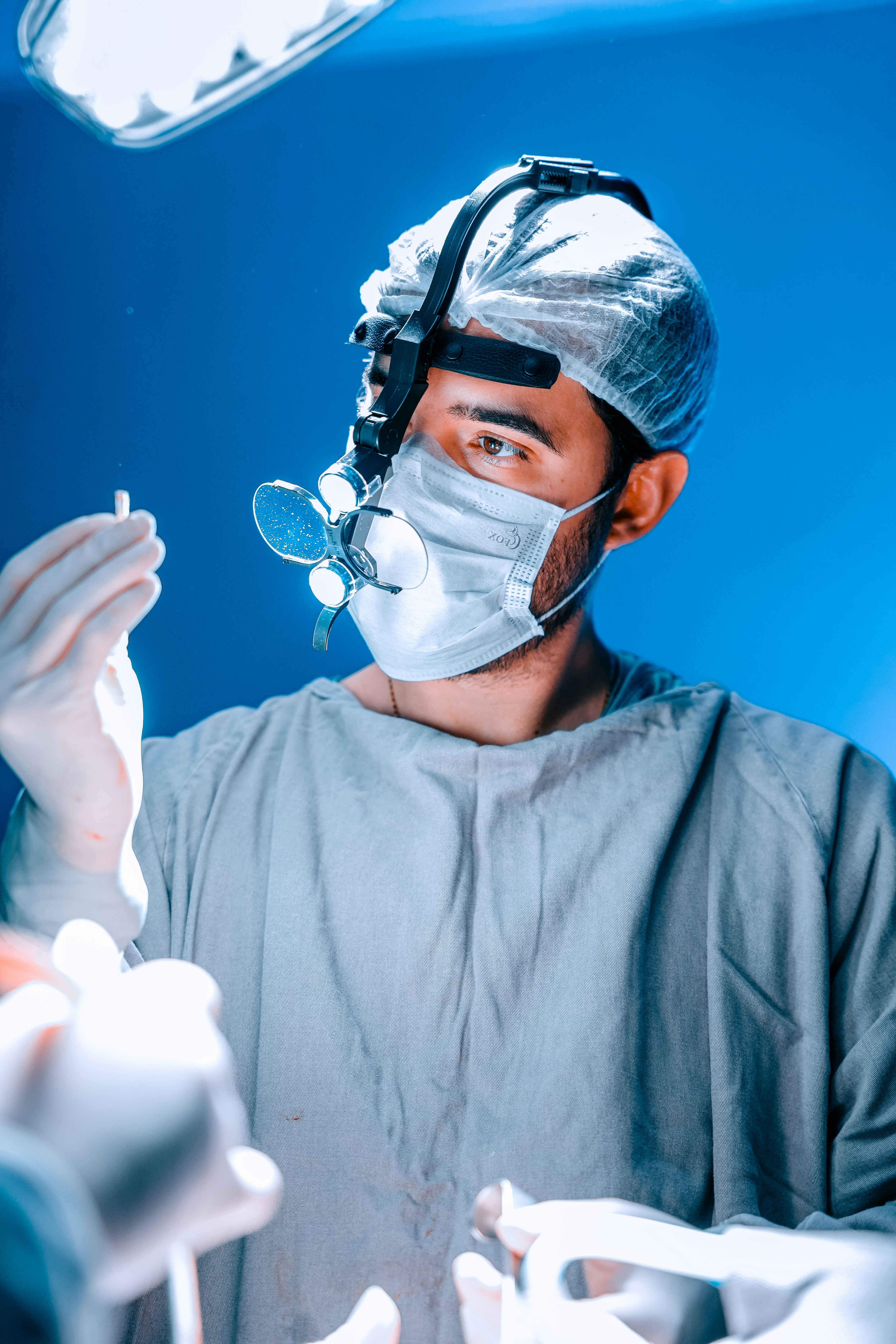 A surgeon examines a medical instrument during surgery. photo – Free ...