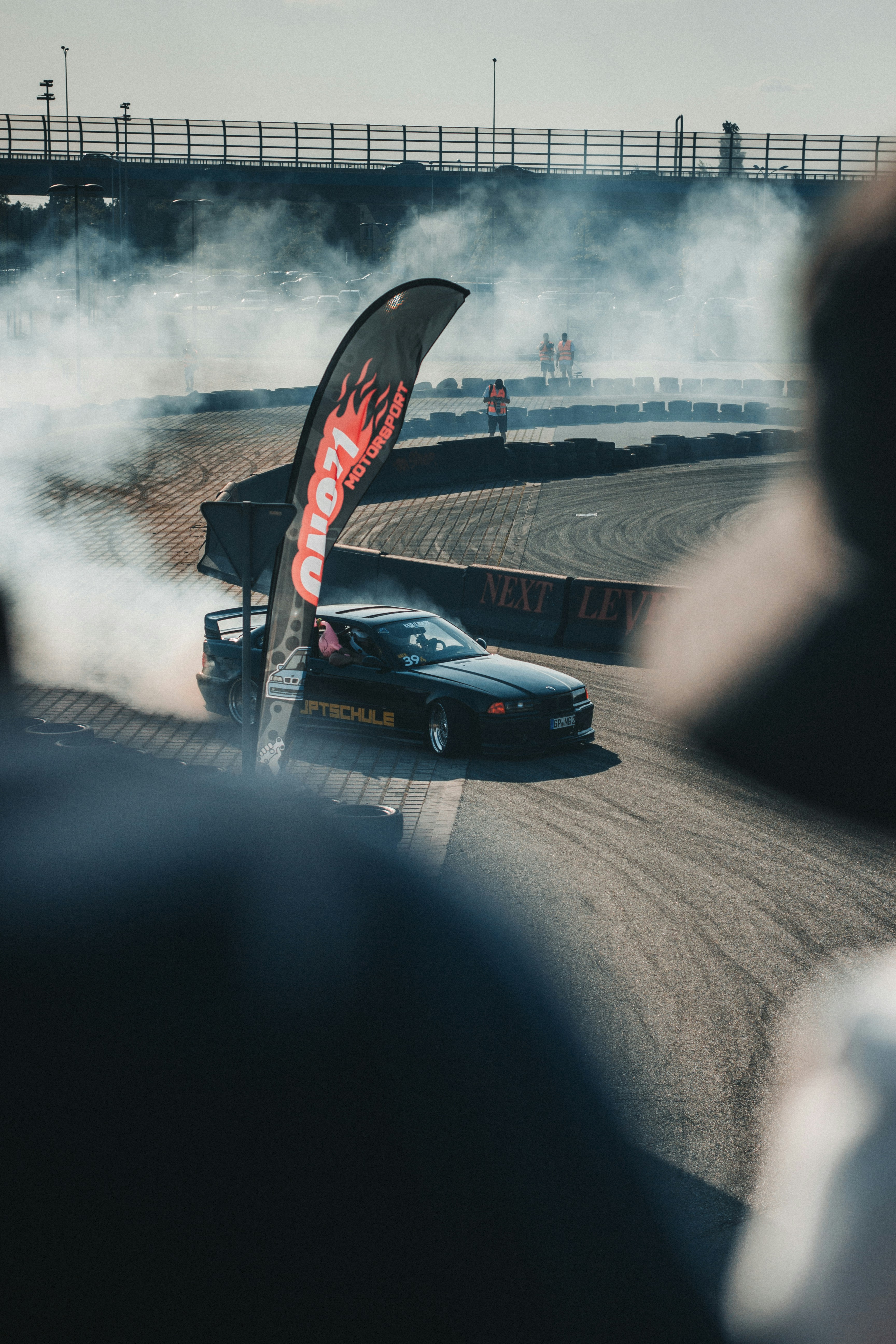 Smoke, Speed, and a Banner: A Black Drift Car Dominates a Curved Track