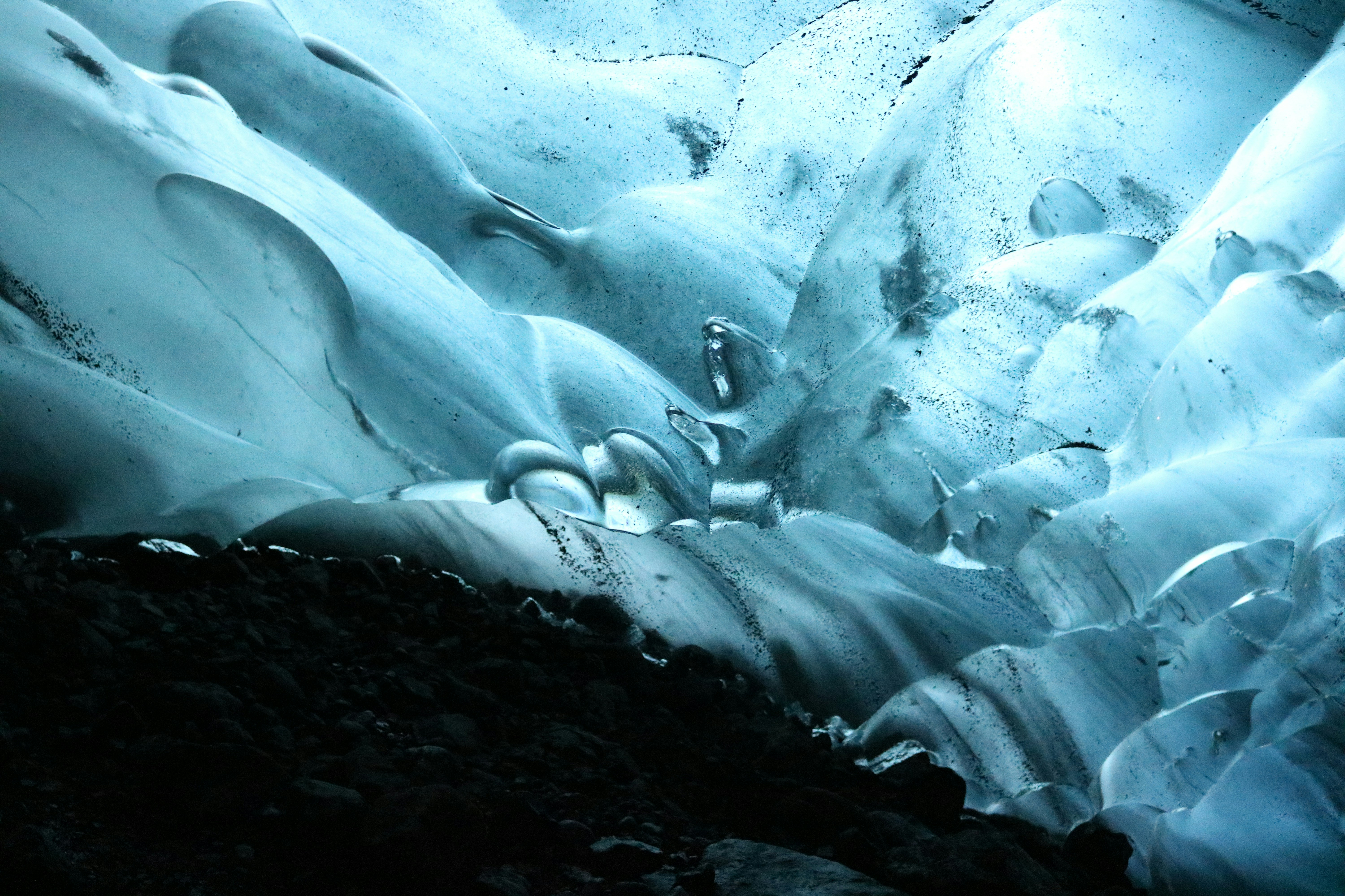 Intricate patterns of ice and rock create a mesmerizing abstract landscape within a glacier cave.