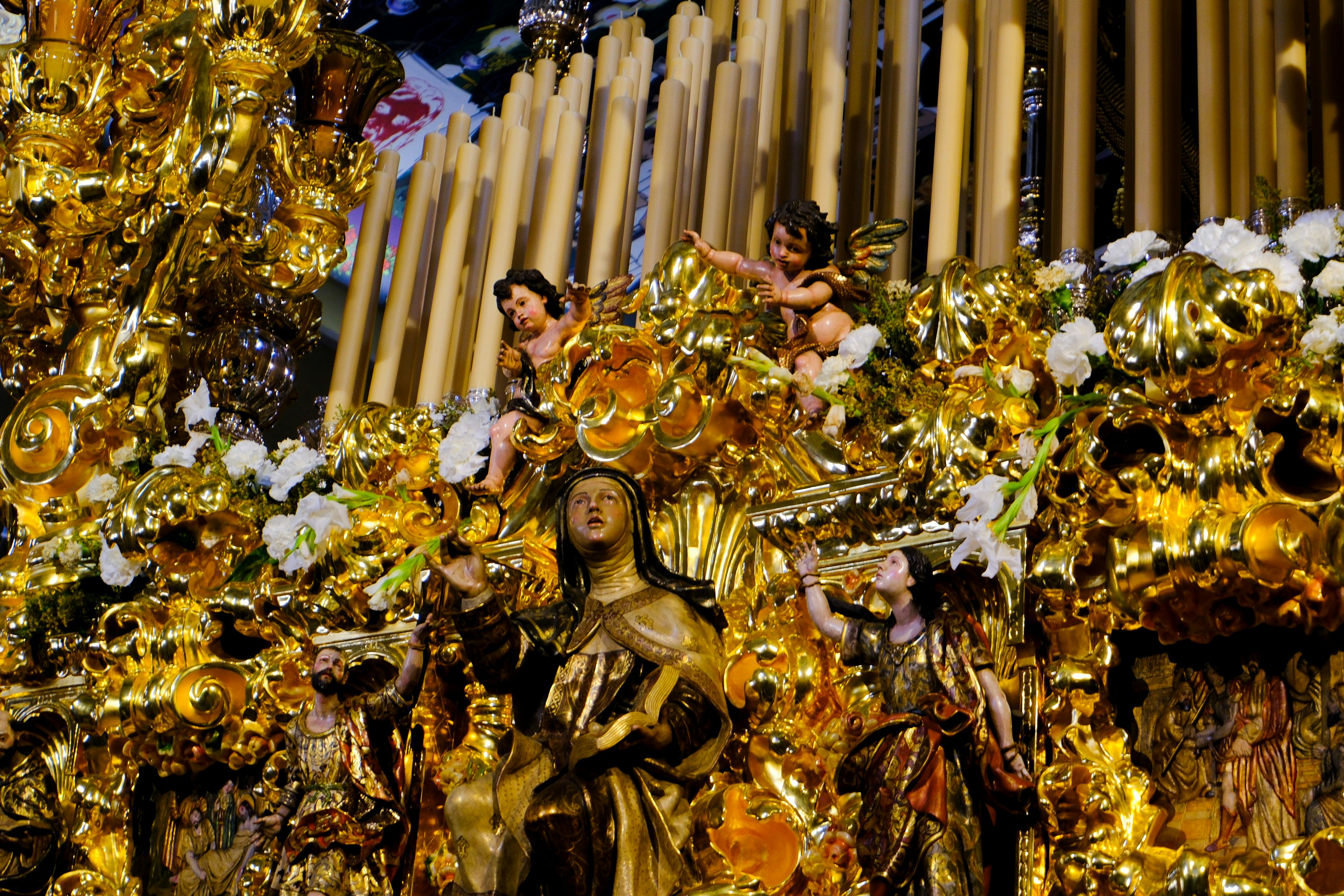 Intricately designed altar adorned with golden figures and floral decorations, showcasing religious artistry and devotion.