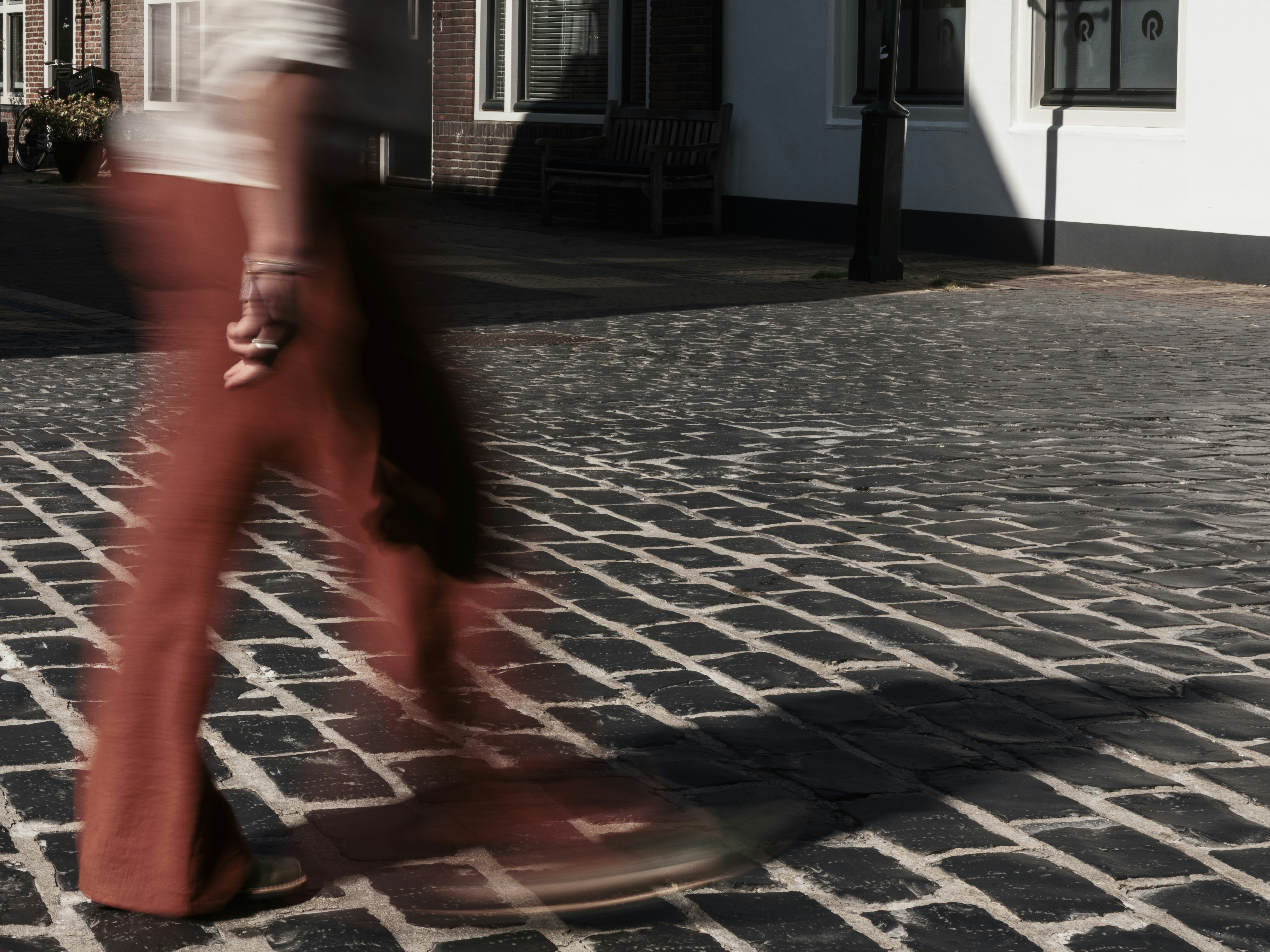 Footsteps in Time: Blurred Pedestrian Across a Cobblestone Street