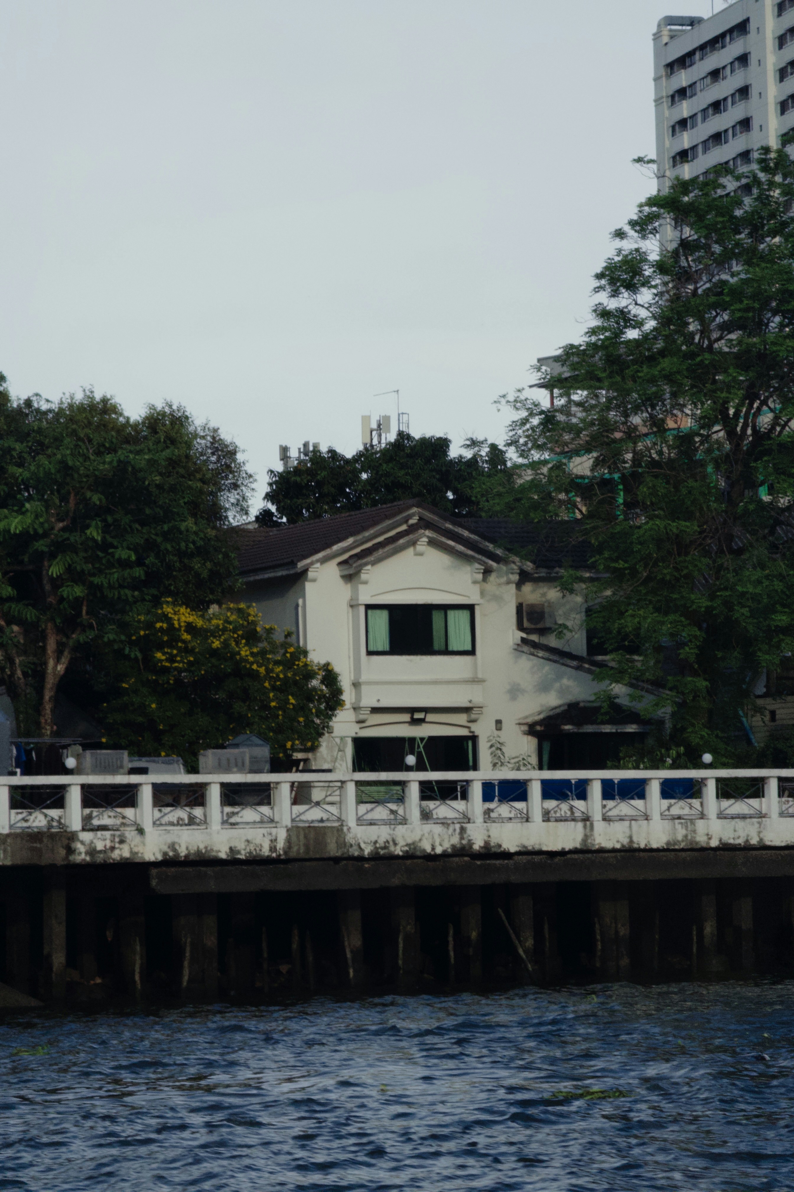 White Riverside House Framed by Urban Greenery and Waterway