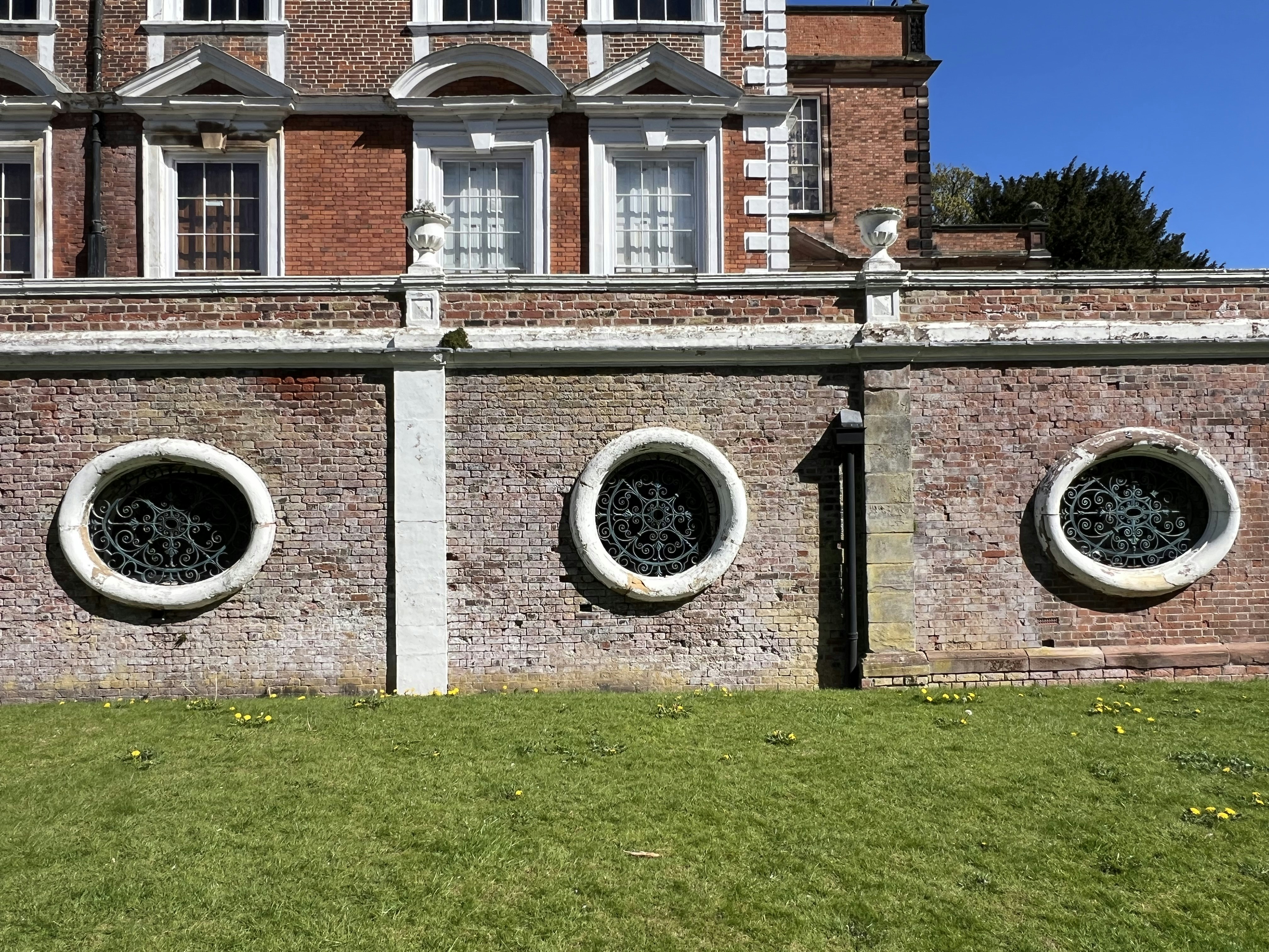 Sunlit Oculus: Three Circular Windows Guard a Brick Estate