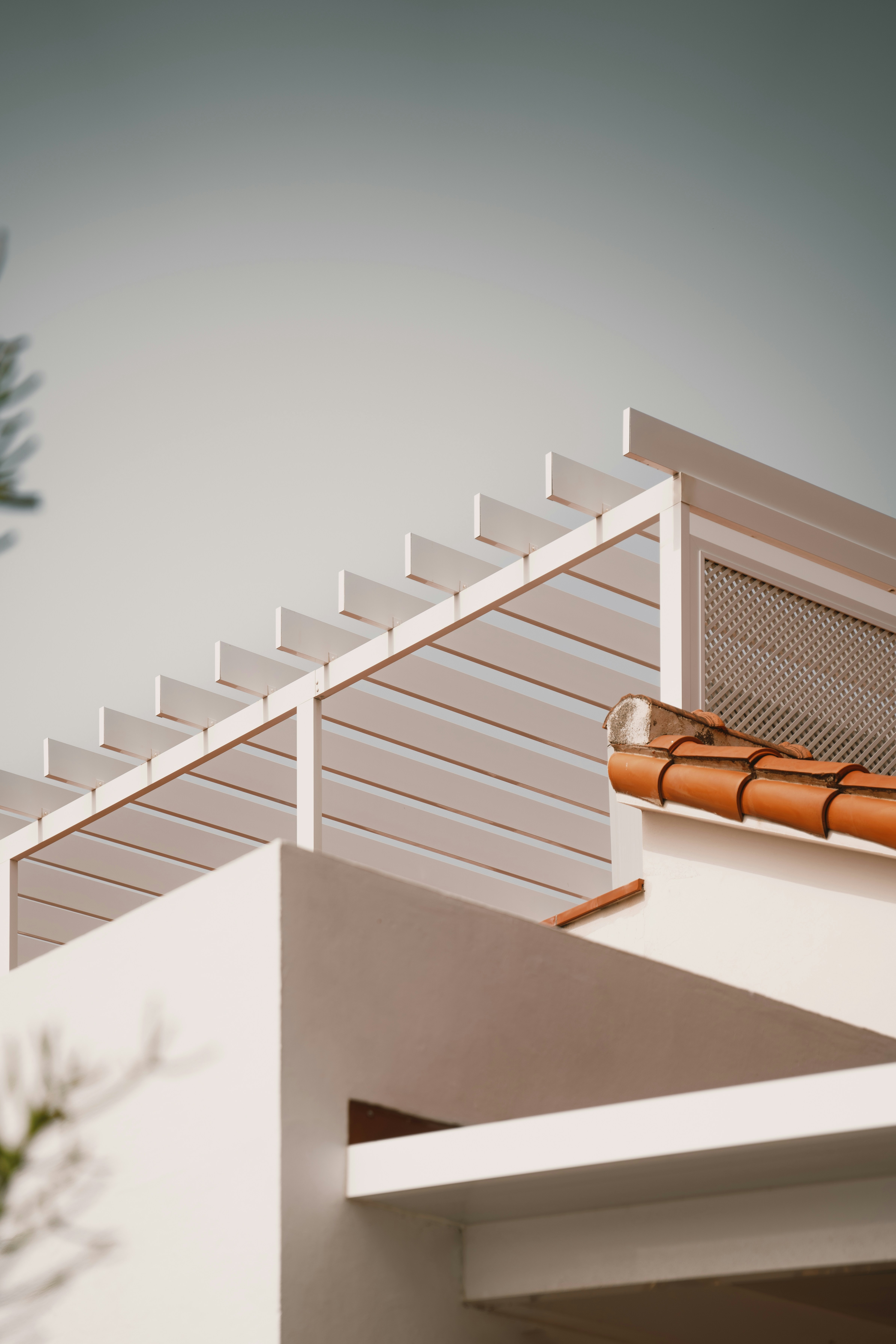 Minimalist rooftop structure featuring clean lines and a terracotta accent. The interplay of shadows and light enhances its architectural appeal.