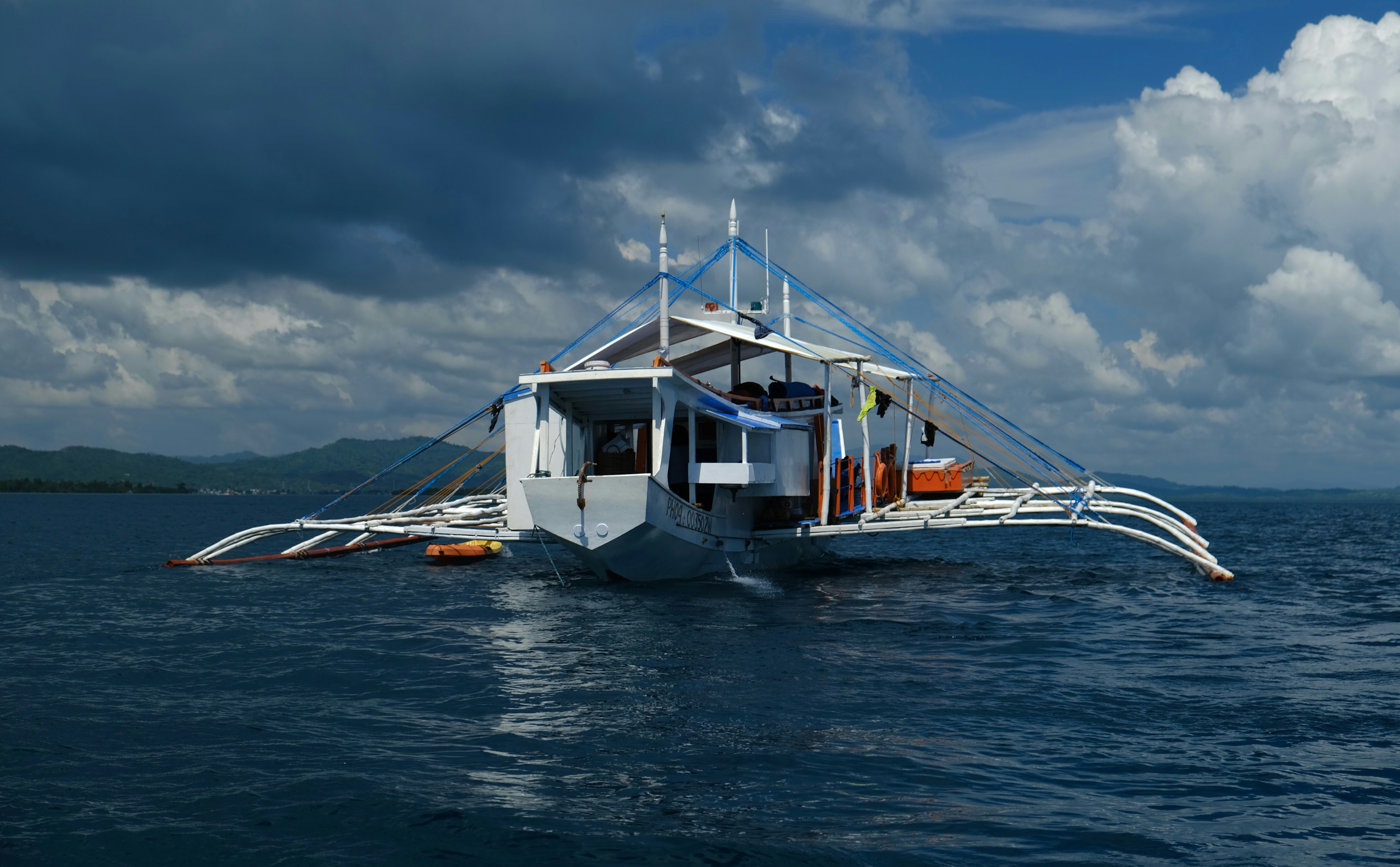 Traditional boat anchored on calm waters under a dramatic sky, showcasing maritime culture and natural beauty.