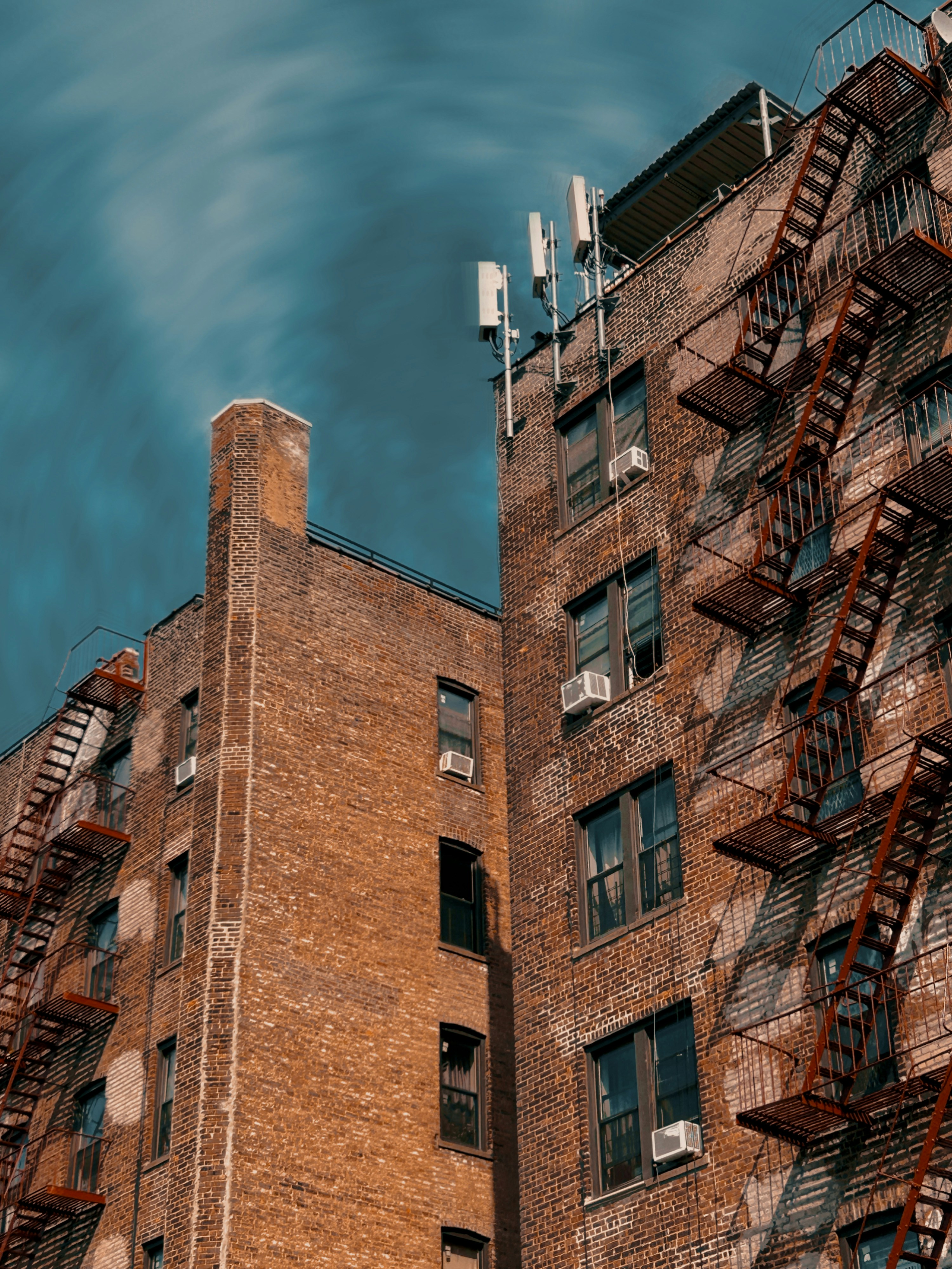 Old brick buildings with fire escapes under a cloudy sky. photo – Free ...