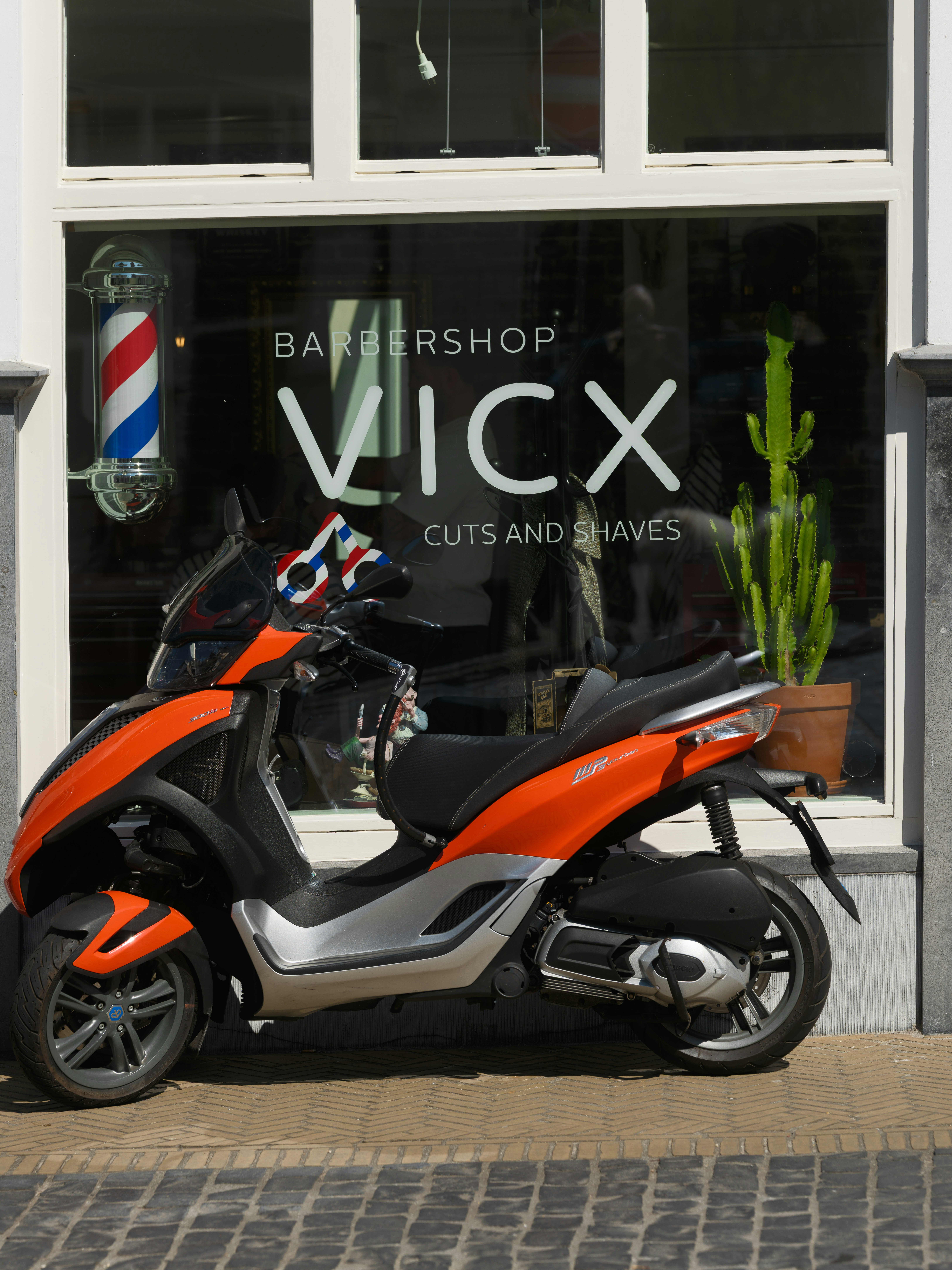 Orange Scooter Before a Barbershop Window: A Quiet Urban Frame