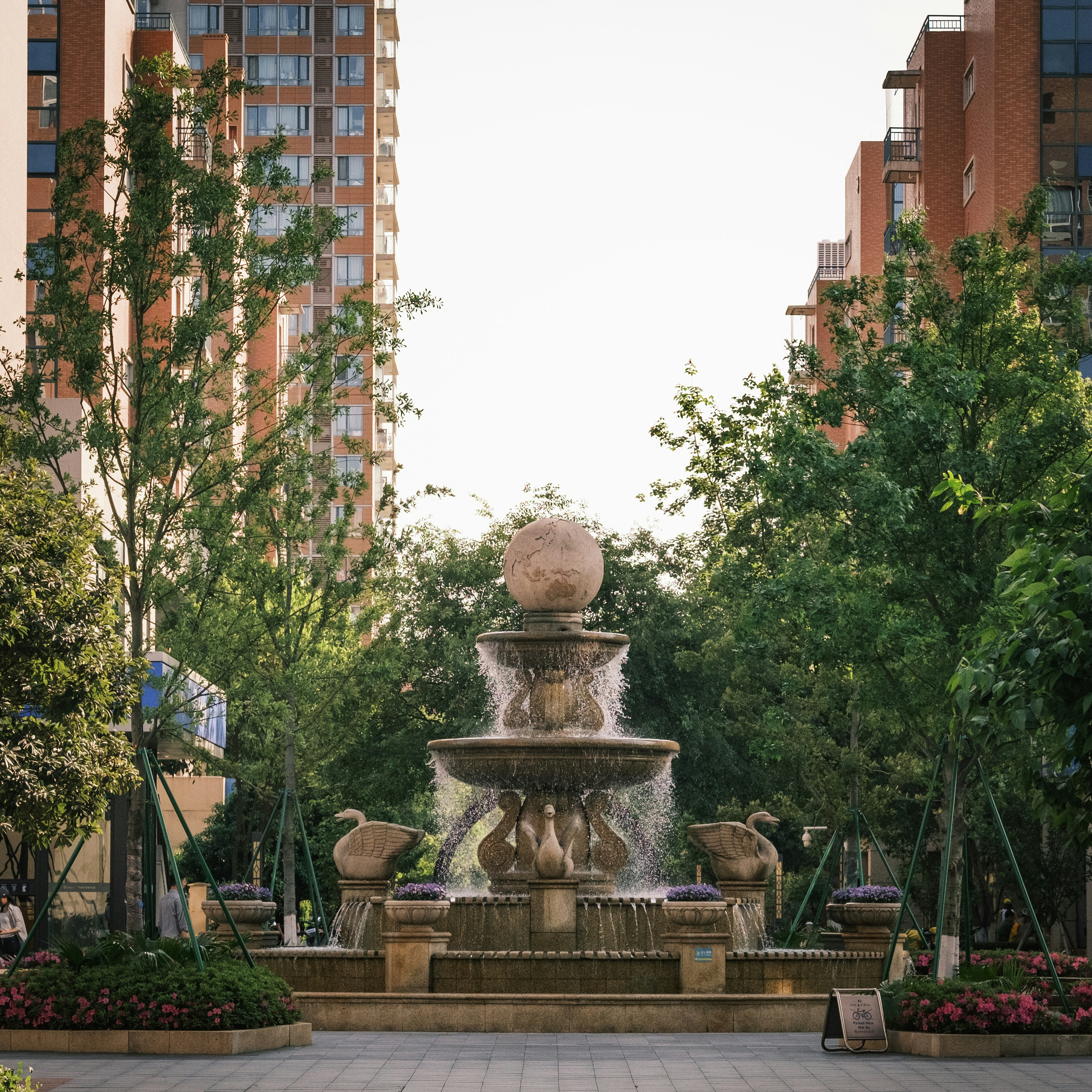 A beautiful fountain stands between tall buildings. photo – Free ...