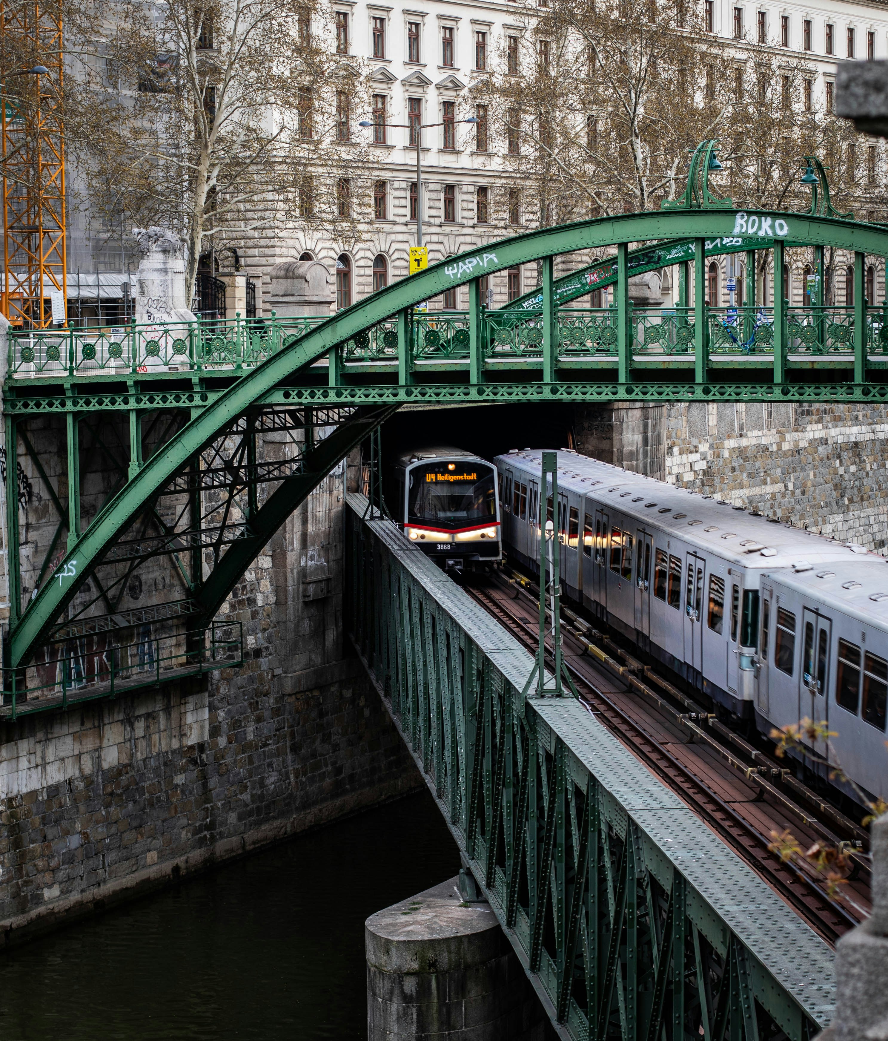 Emerald Arch Over Rails: A Train Wends Through a Historic Riverside Quarter
