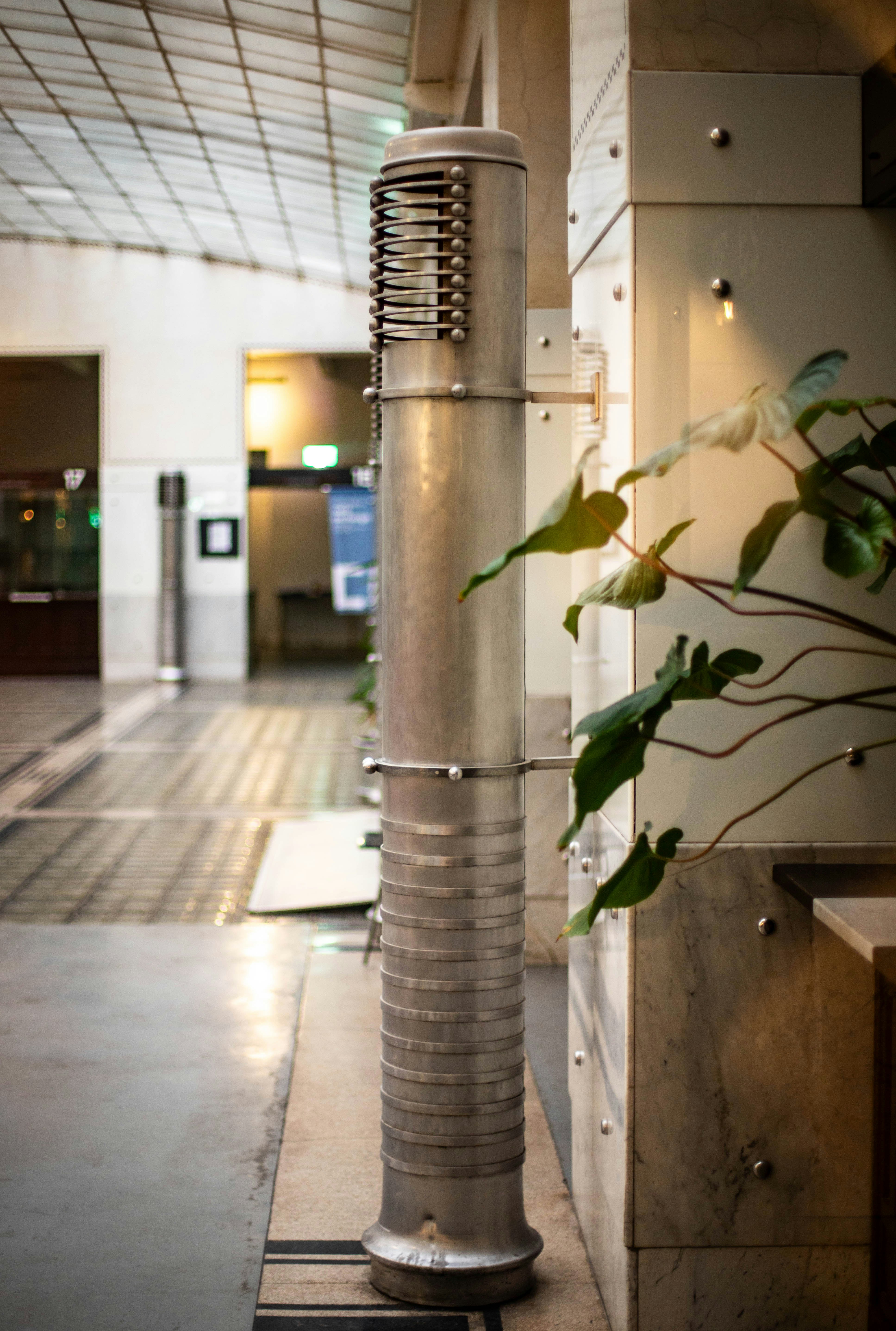 An industrial pillar stands near greenery in a building. photo – Free ...