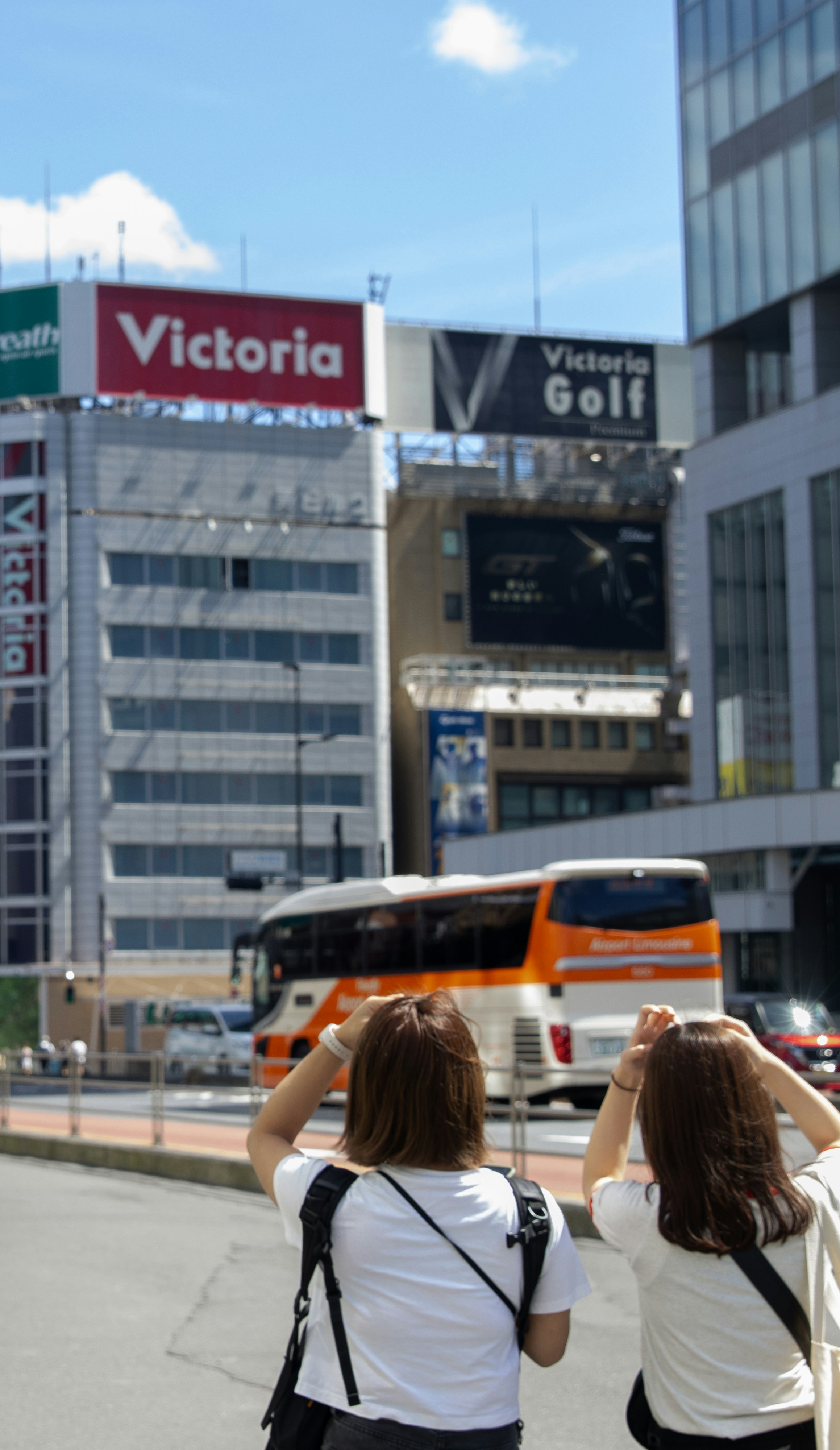Two Tourists Pause to Snap a Bus-Passed City Scene