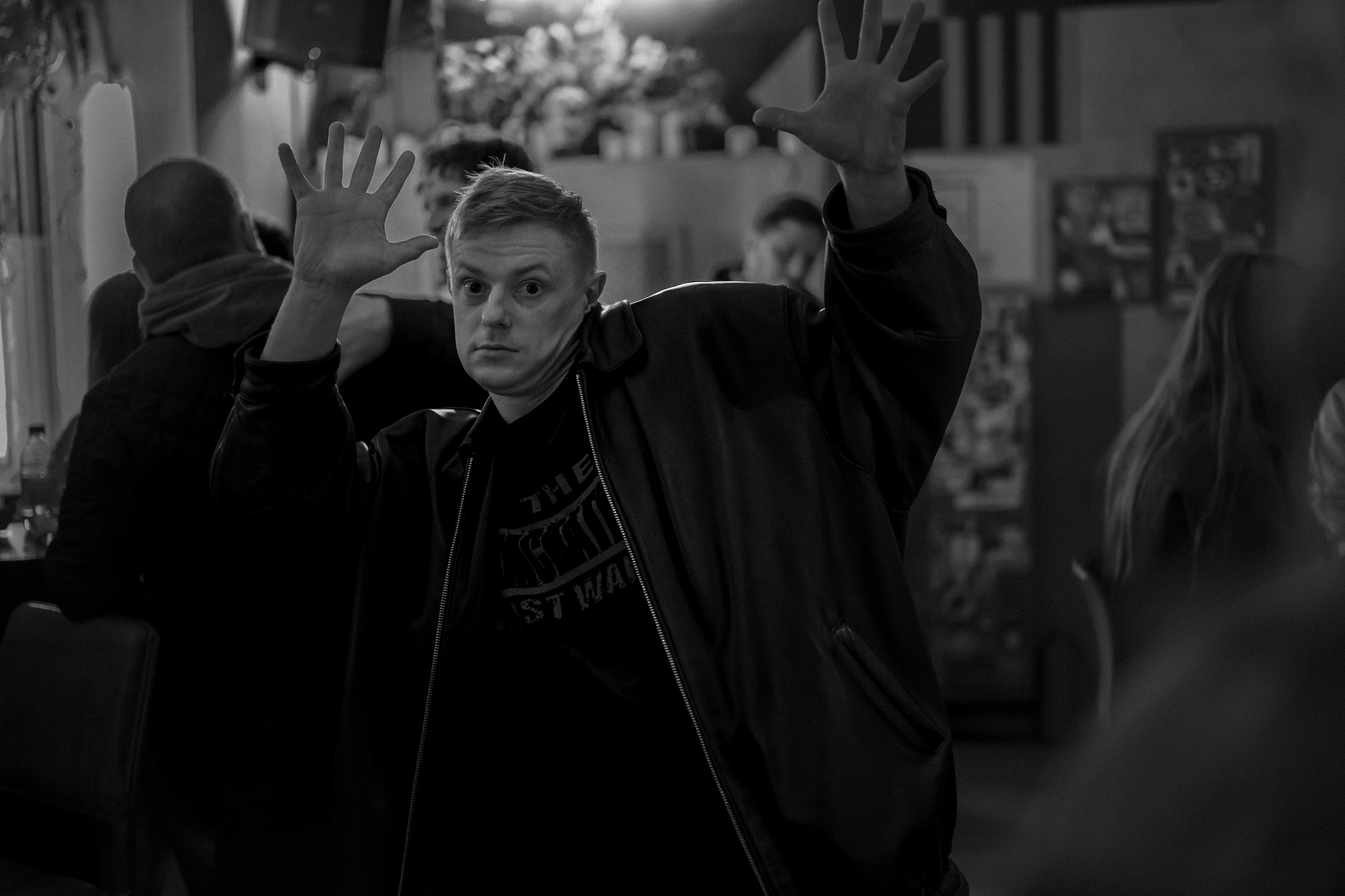 Monochrome Moment: The Man with Raised Hands Amid a Crowded Room