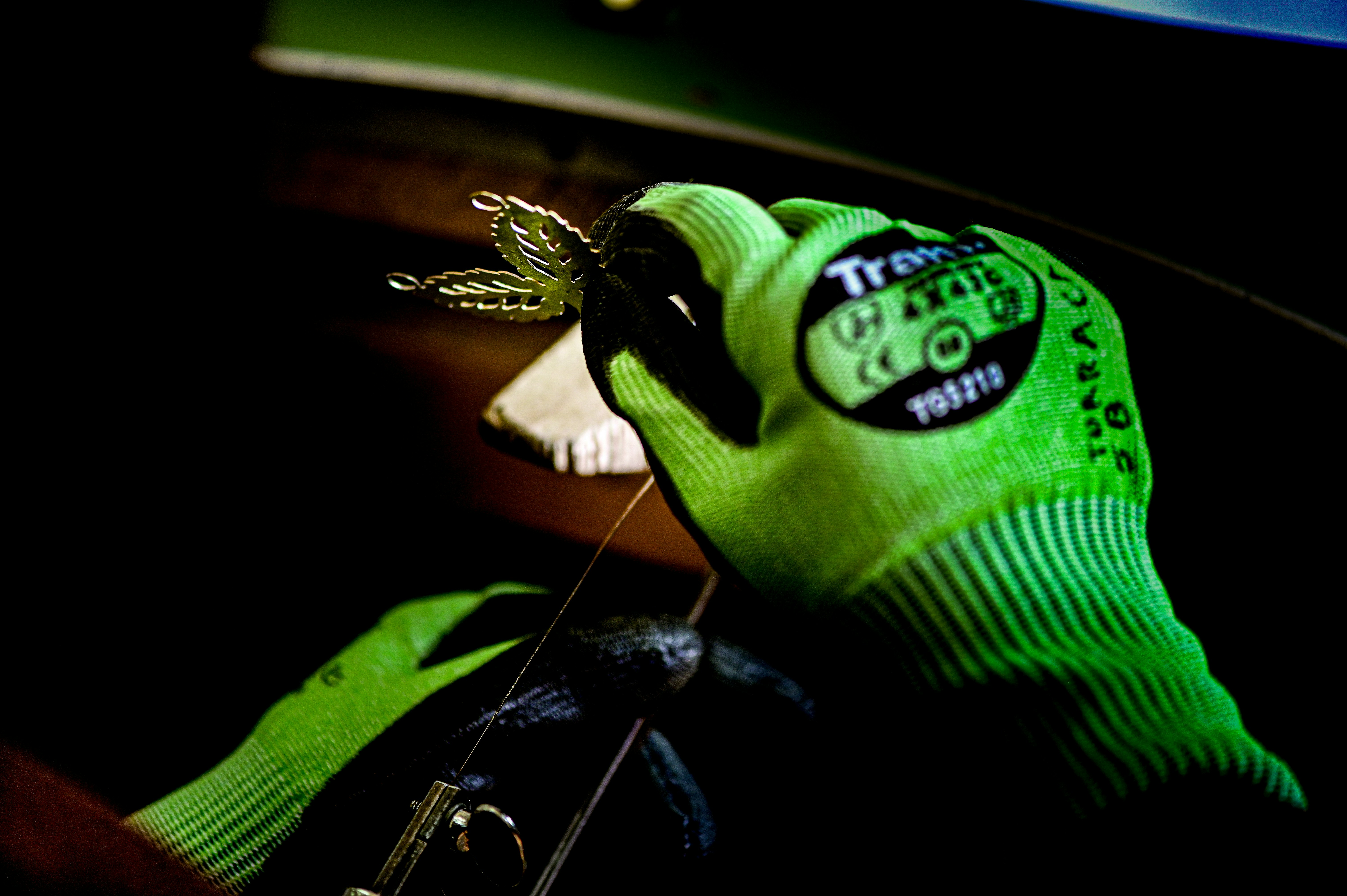Green glove surgical precision: catching a jewel between pliers under dim light