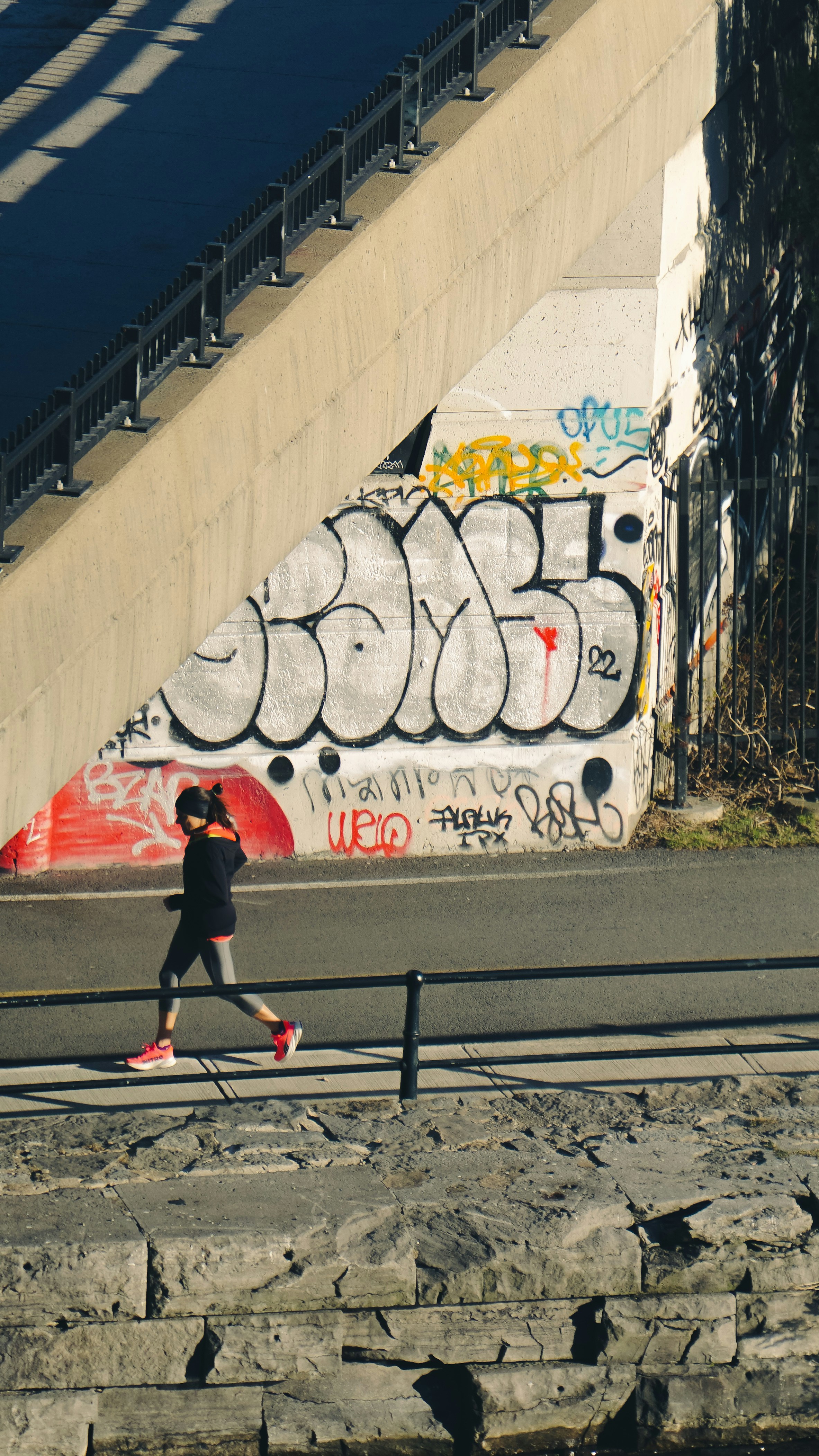 Red-Sneaker Run Beneath a Graffitied Overpass