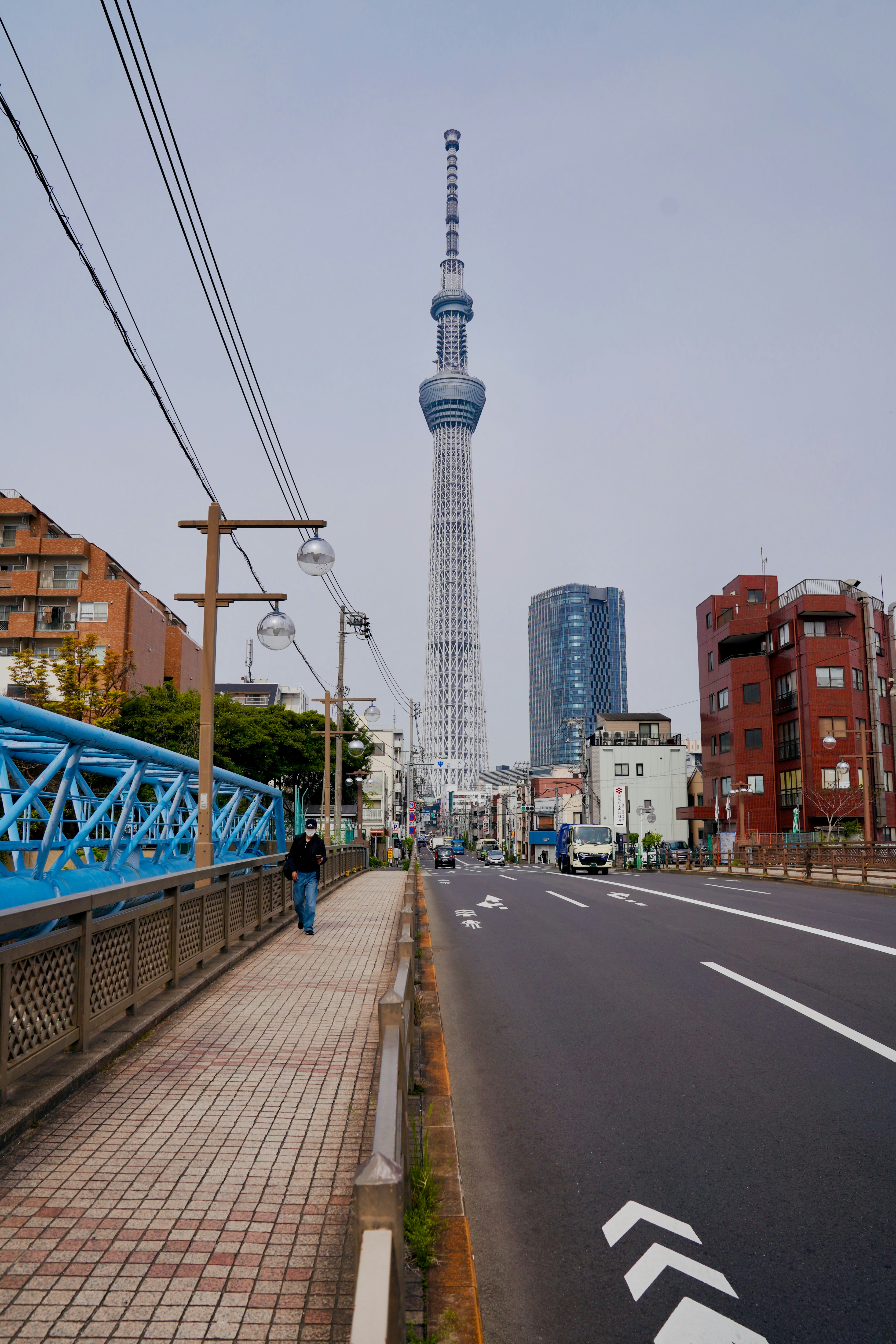 Tokyo Skytree rises majestically amidst urban architecture, framed by streets and buildings. The scene captures the blend of modernity and city life.