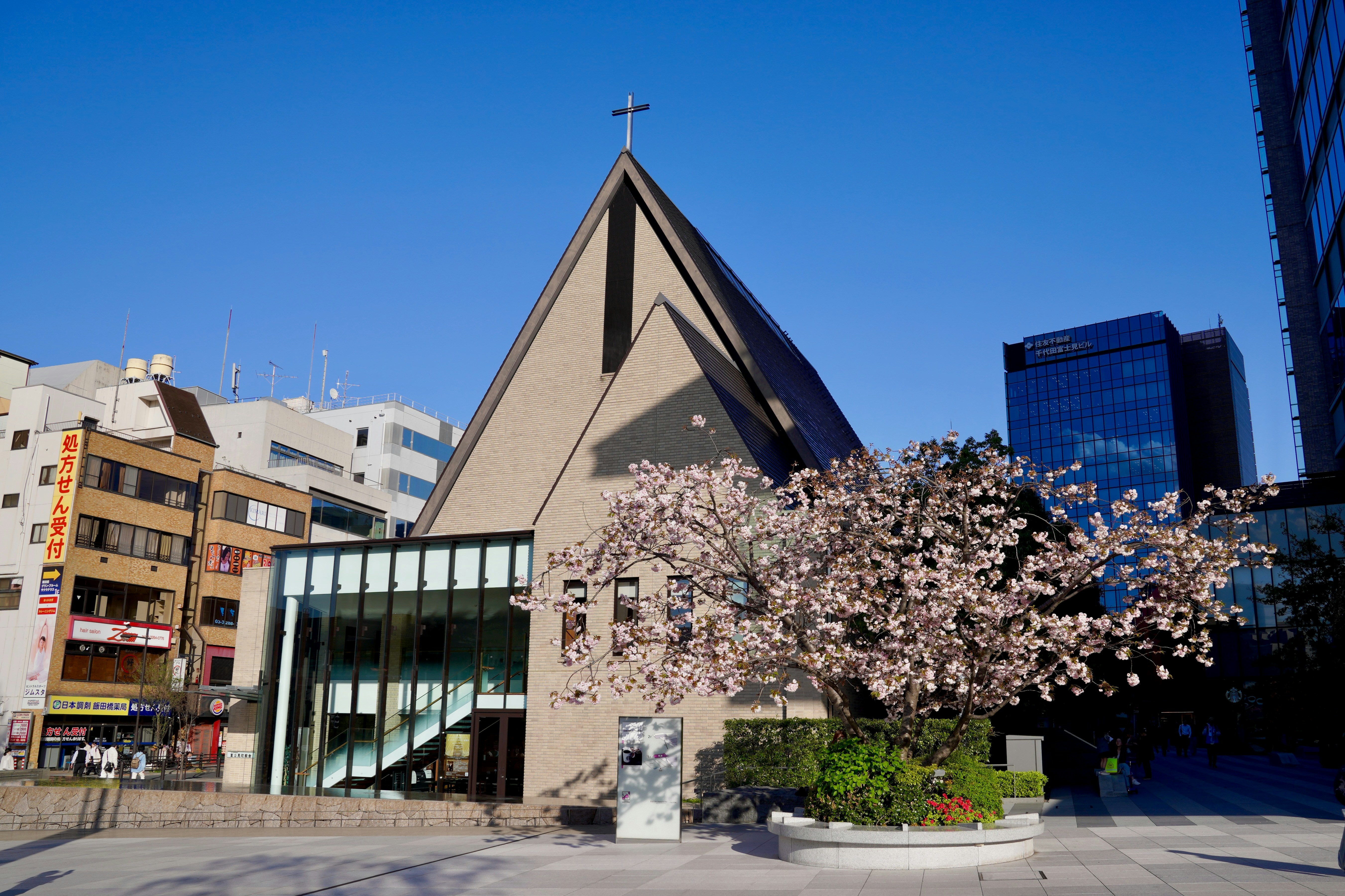 Chapel in the City Square: Cherry Blossoms Framing a Modern Triangular Roof