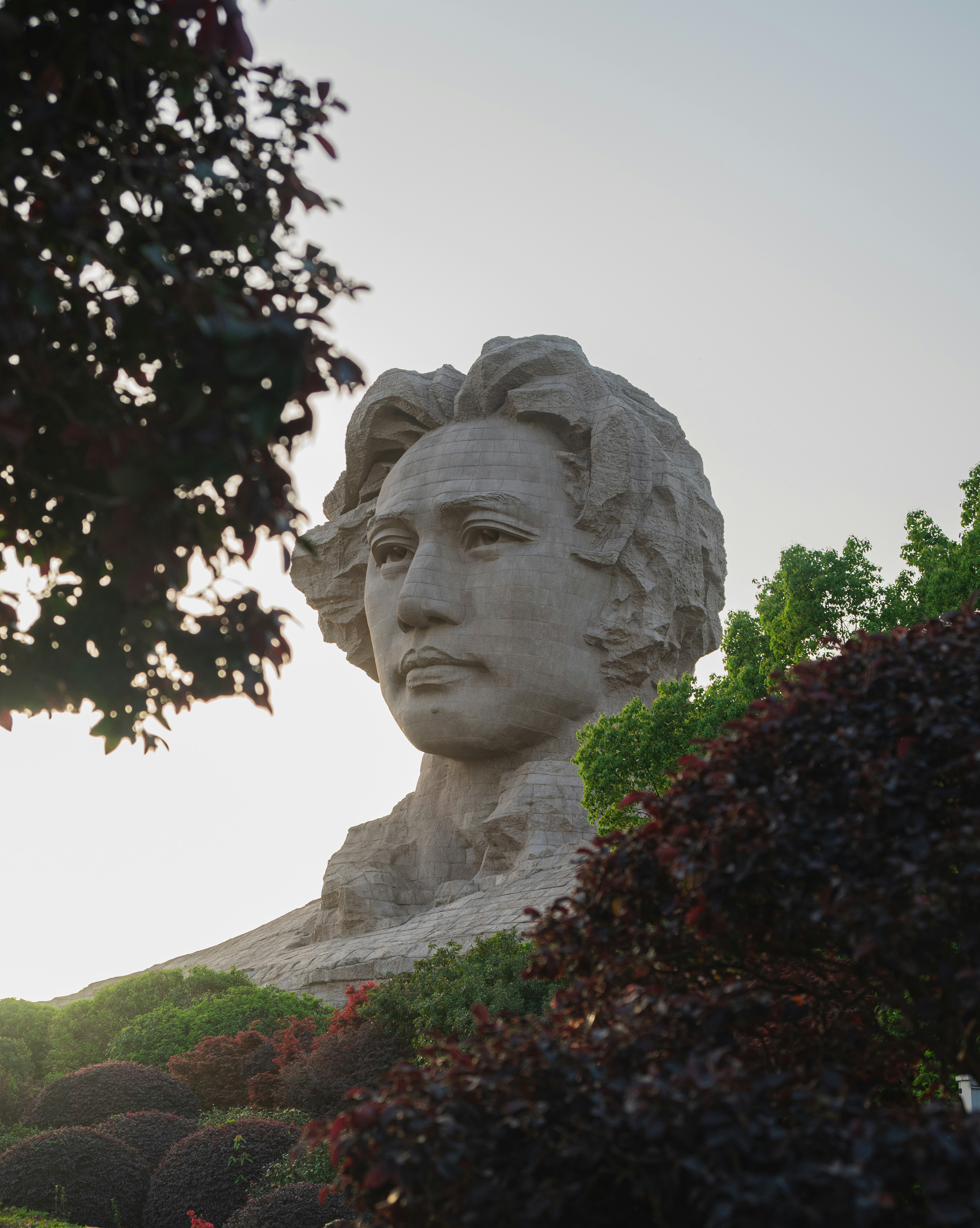 A large stone bust is framed by foliage. photo – Free Woman Image on ...