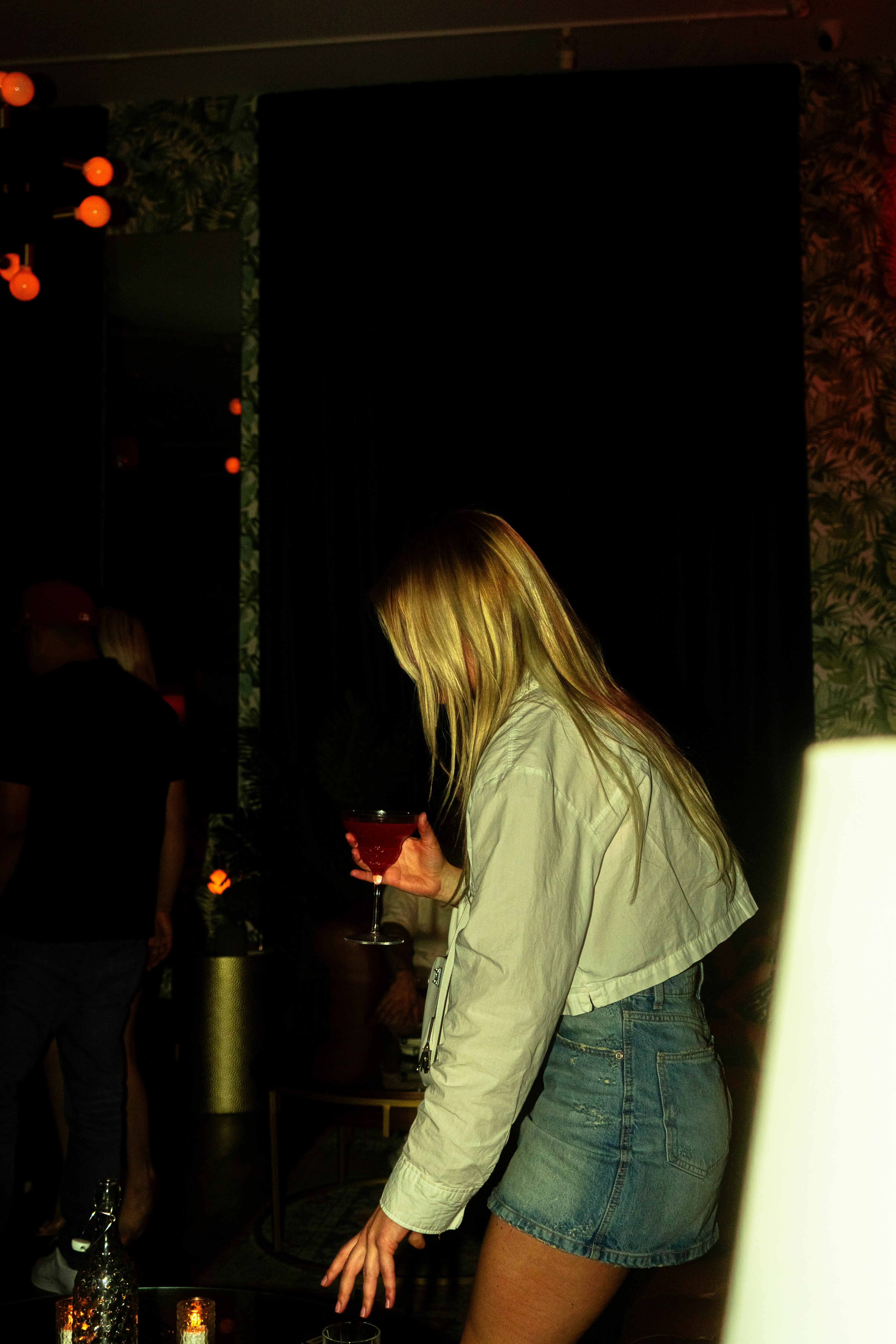 Denim After Dark: A solitary toast in a velvet-lit lounge