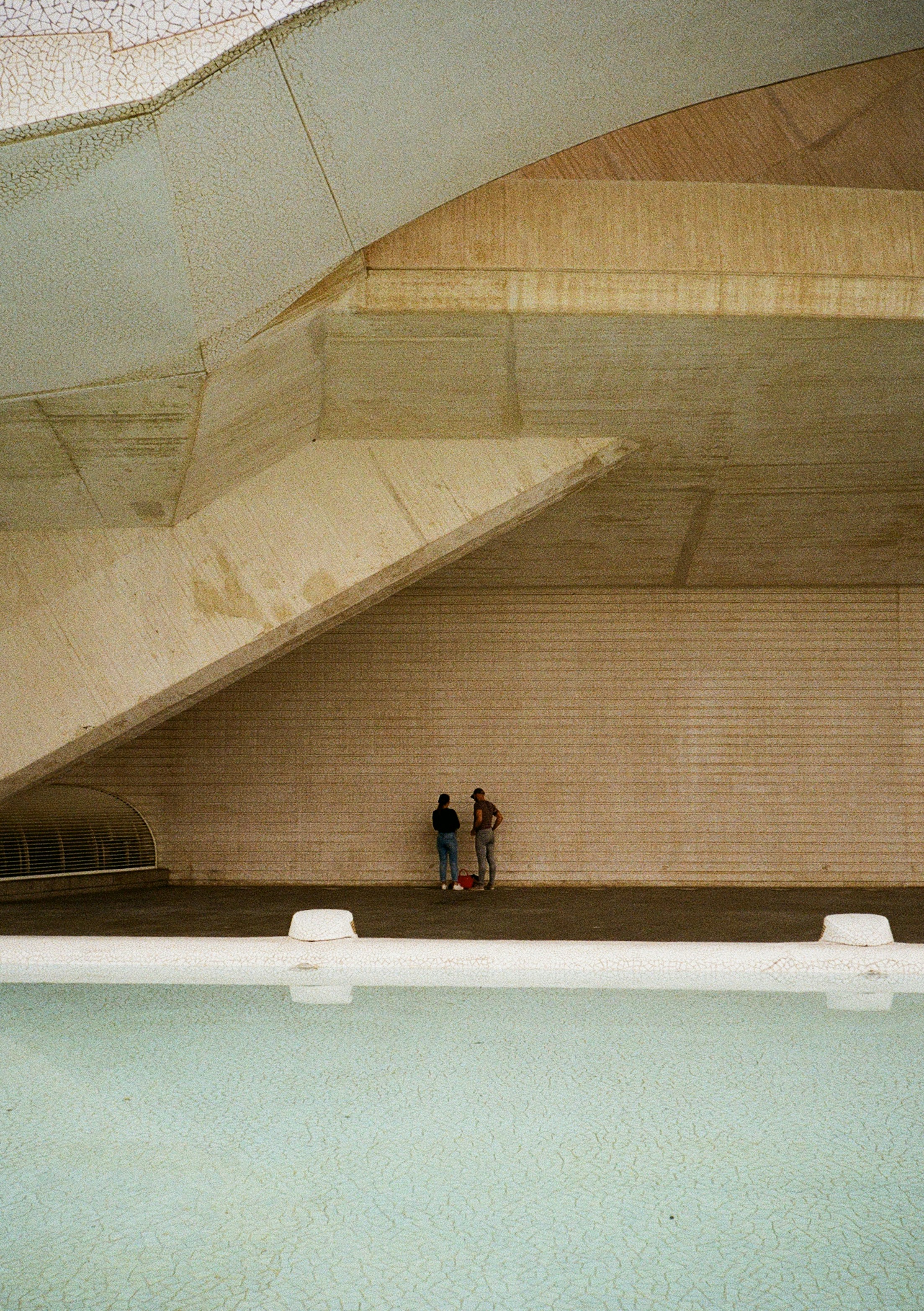 Two people stand beneath a large architectural structure. photo – Free ...