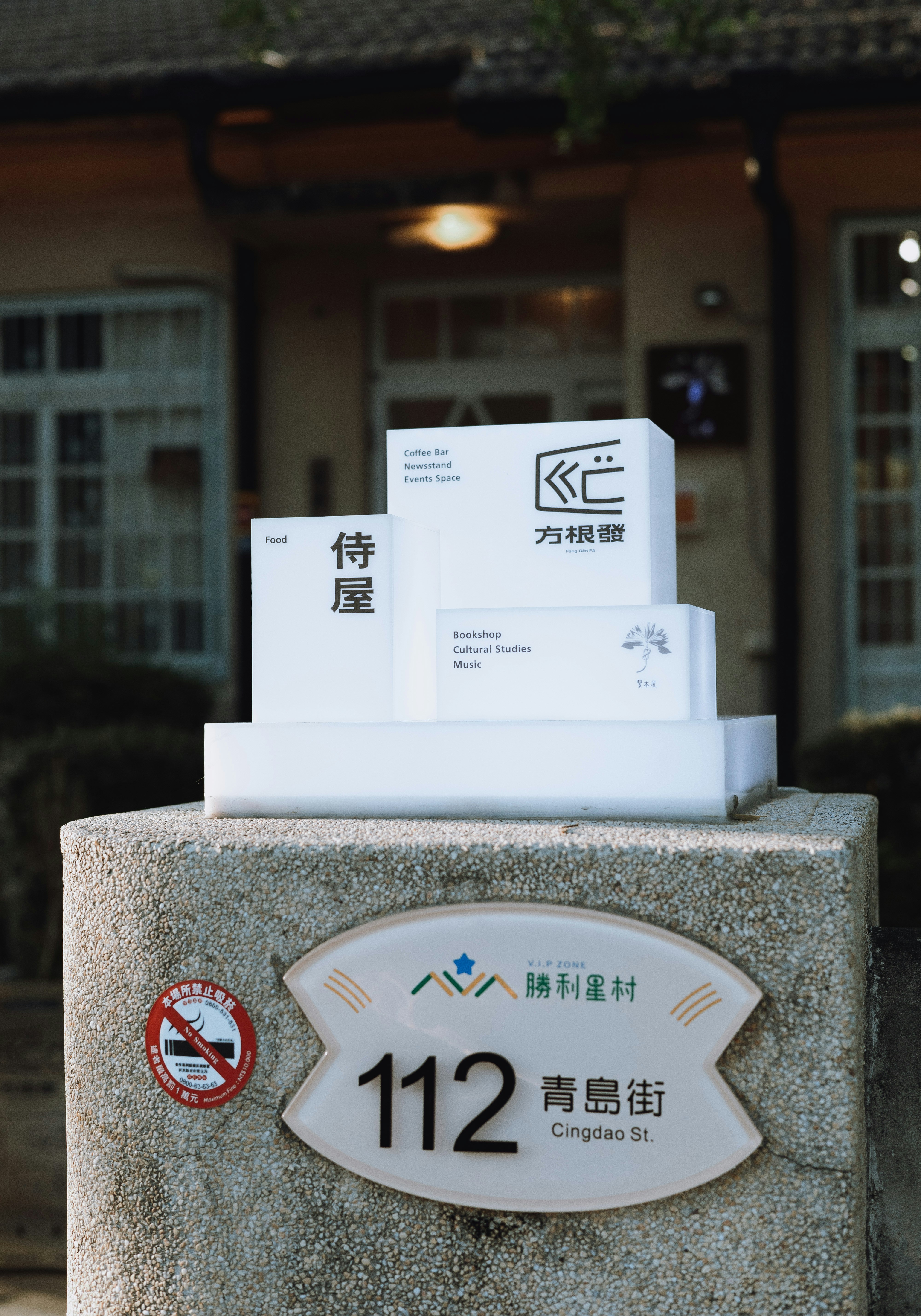Signage on a column stands in front of a building. photo – Free Paper ...