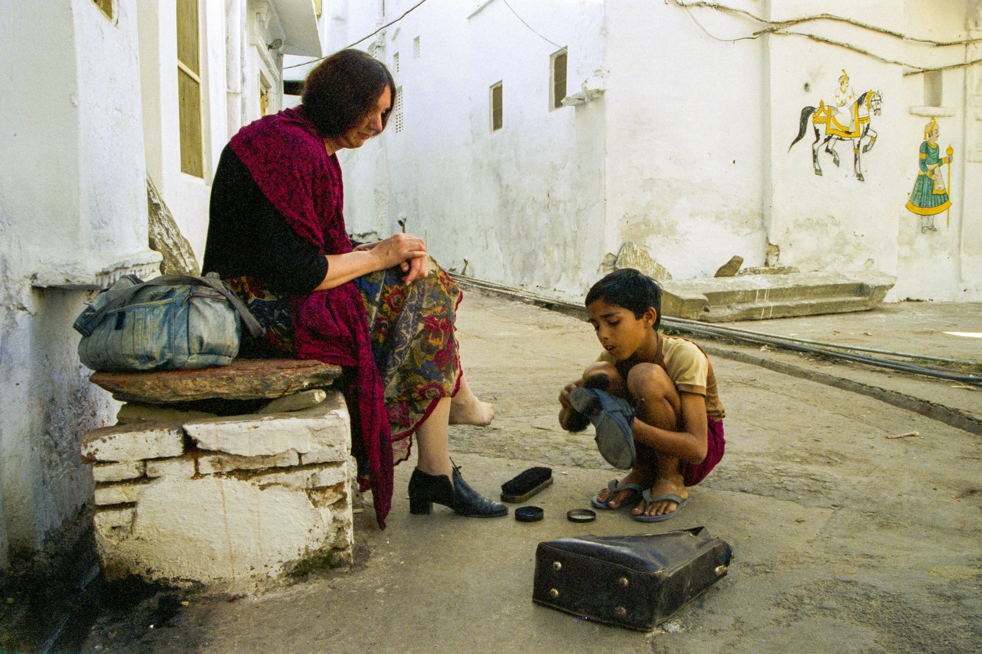 A woman watches a child with his shoes.