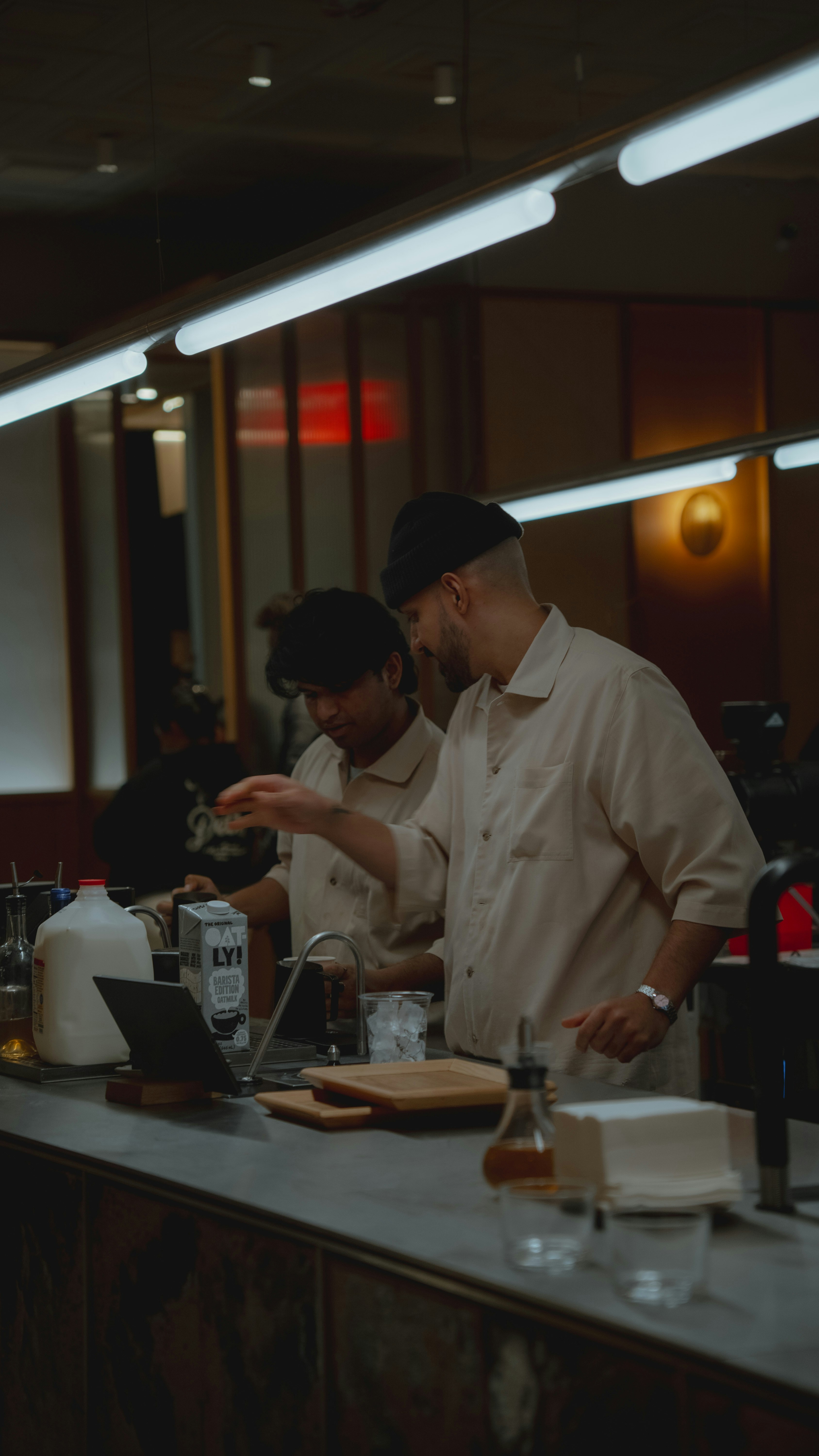 Two baristas interact behind a counter. photo – Free Coffee Image on ...