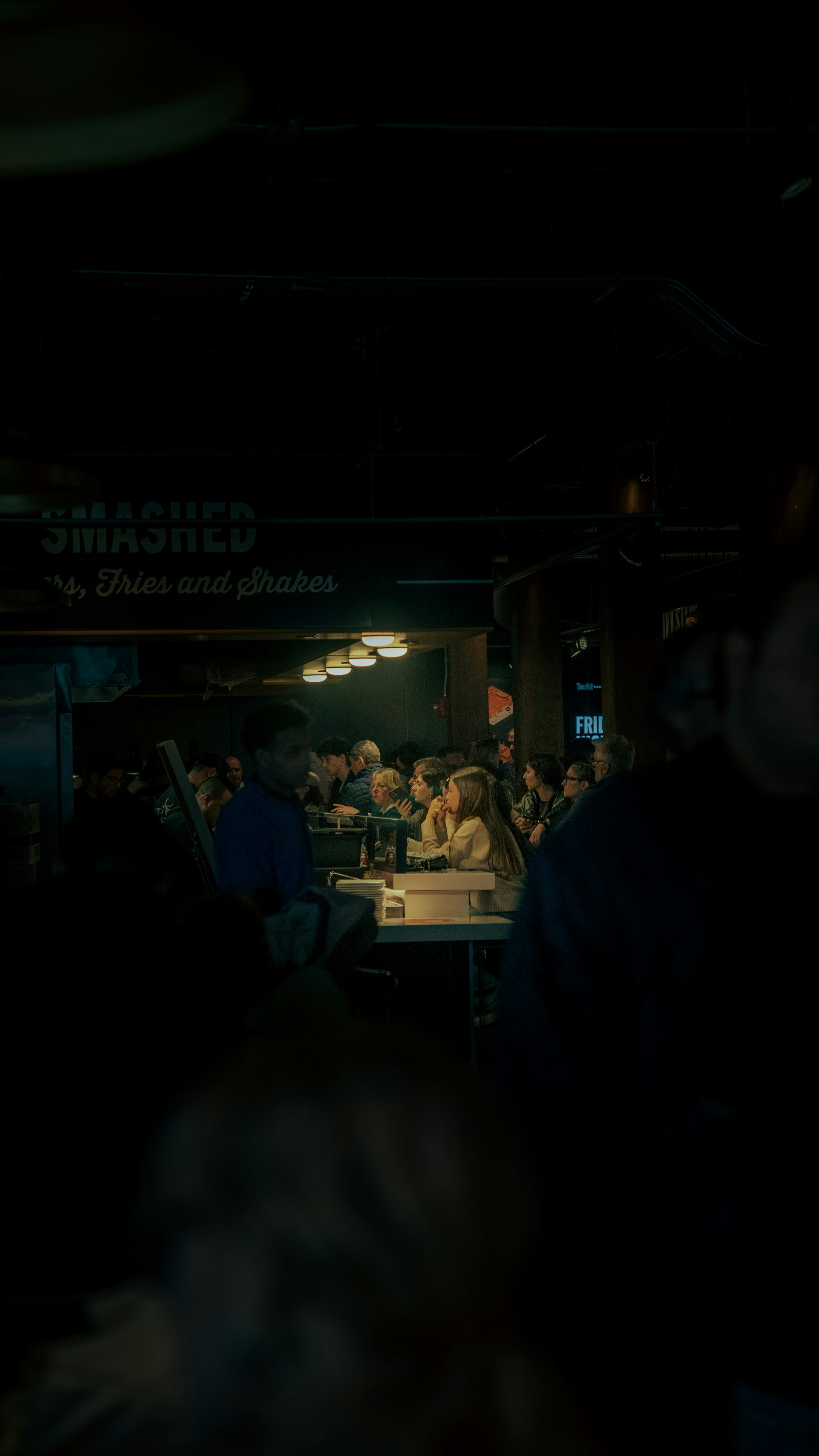 Night Market Glow: Faces Queued Beneath Warm Overhead Lights