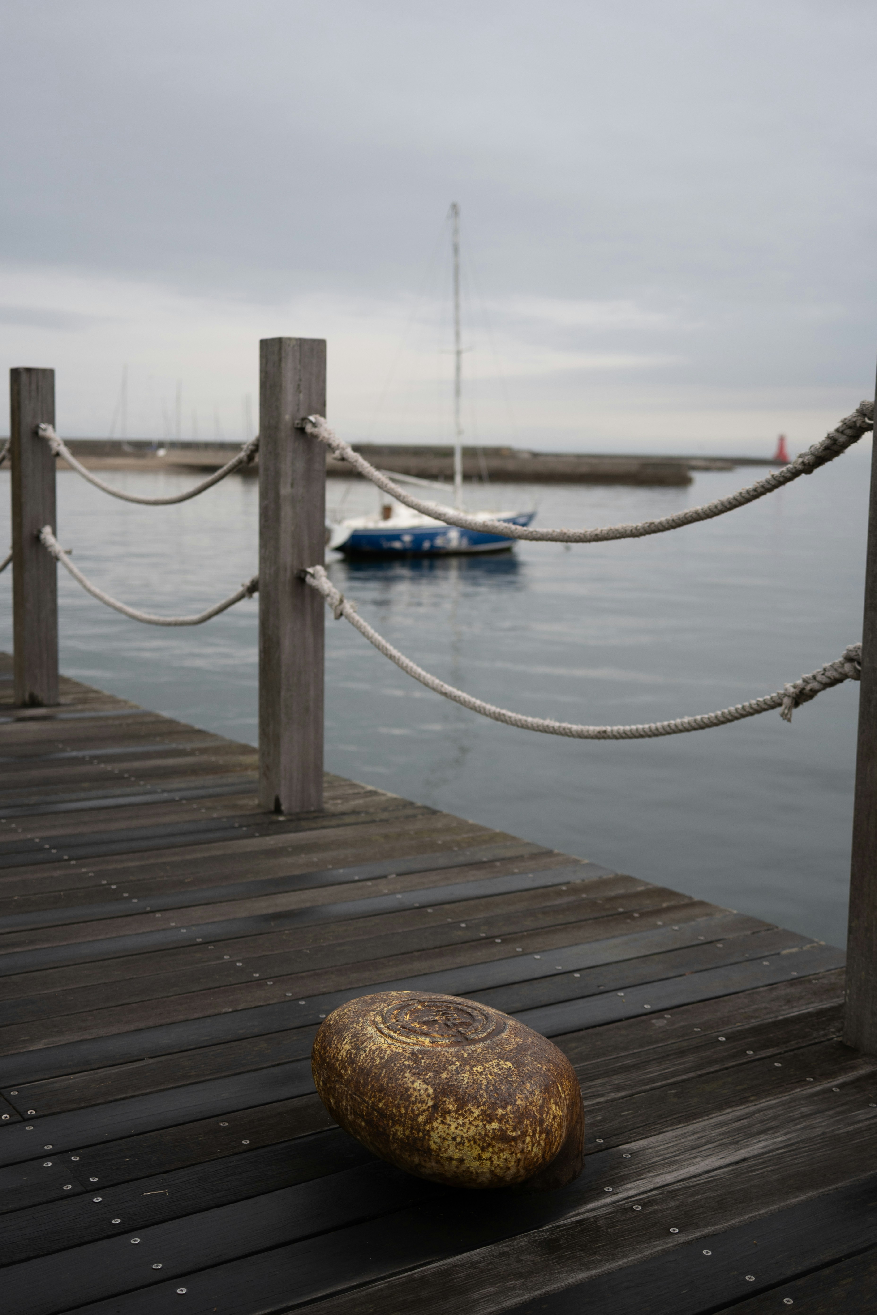 Rust on the Rigging: A Weathered Buoy on a Calm Pier