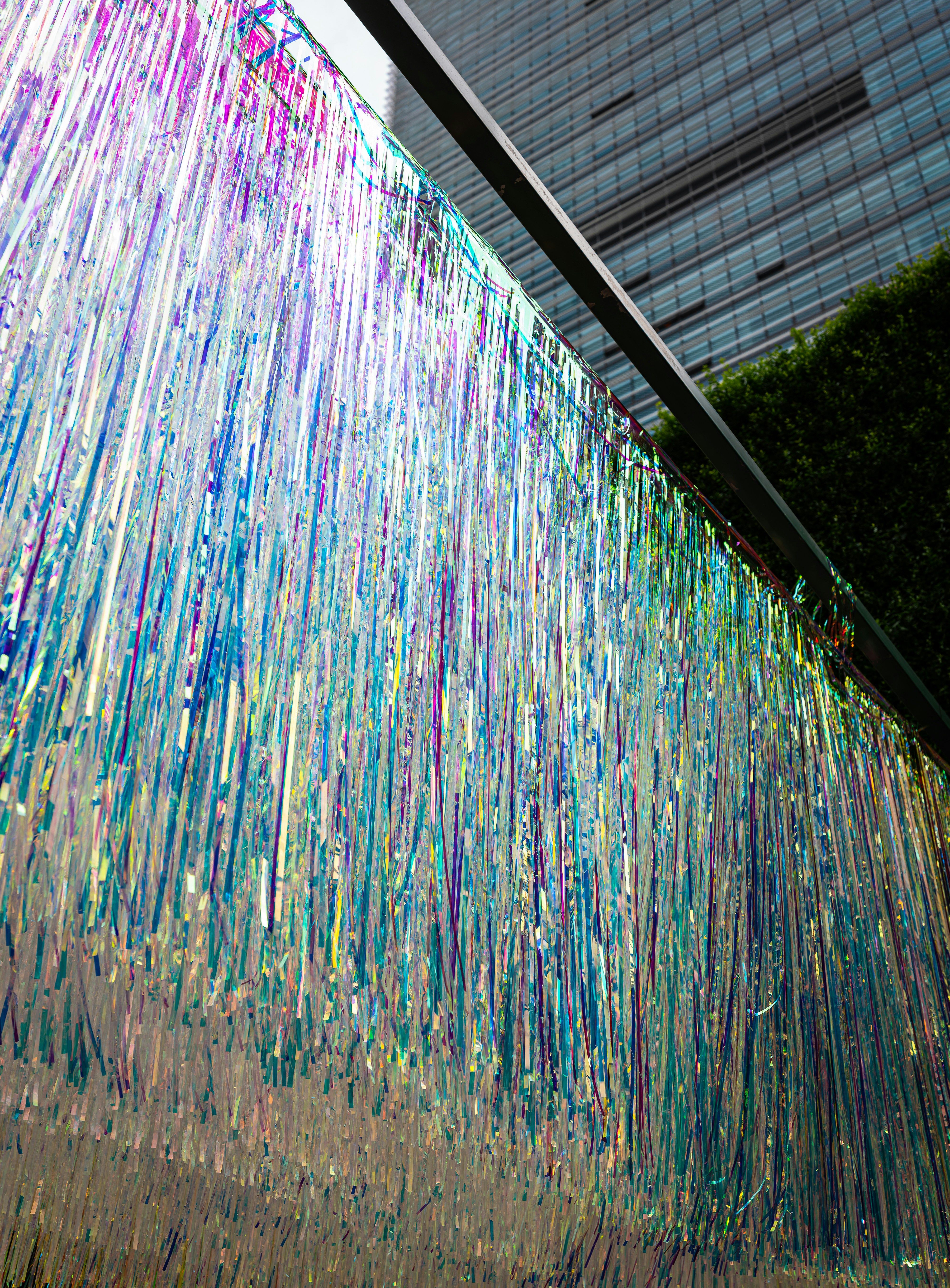 Iridescent Curtain: Color Threads Draped Along a Modern Glass Facade
