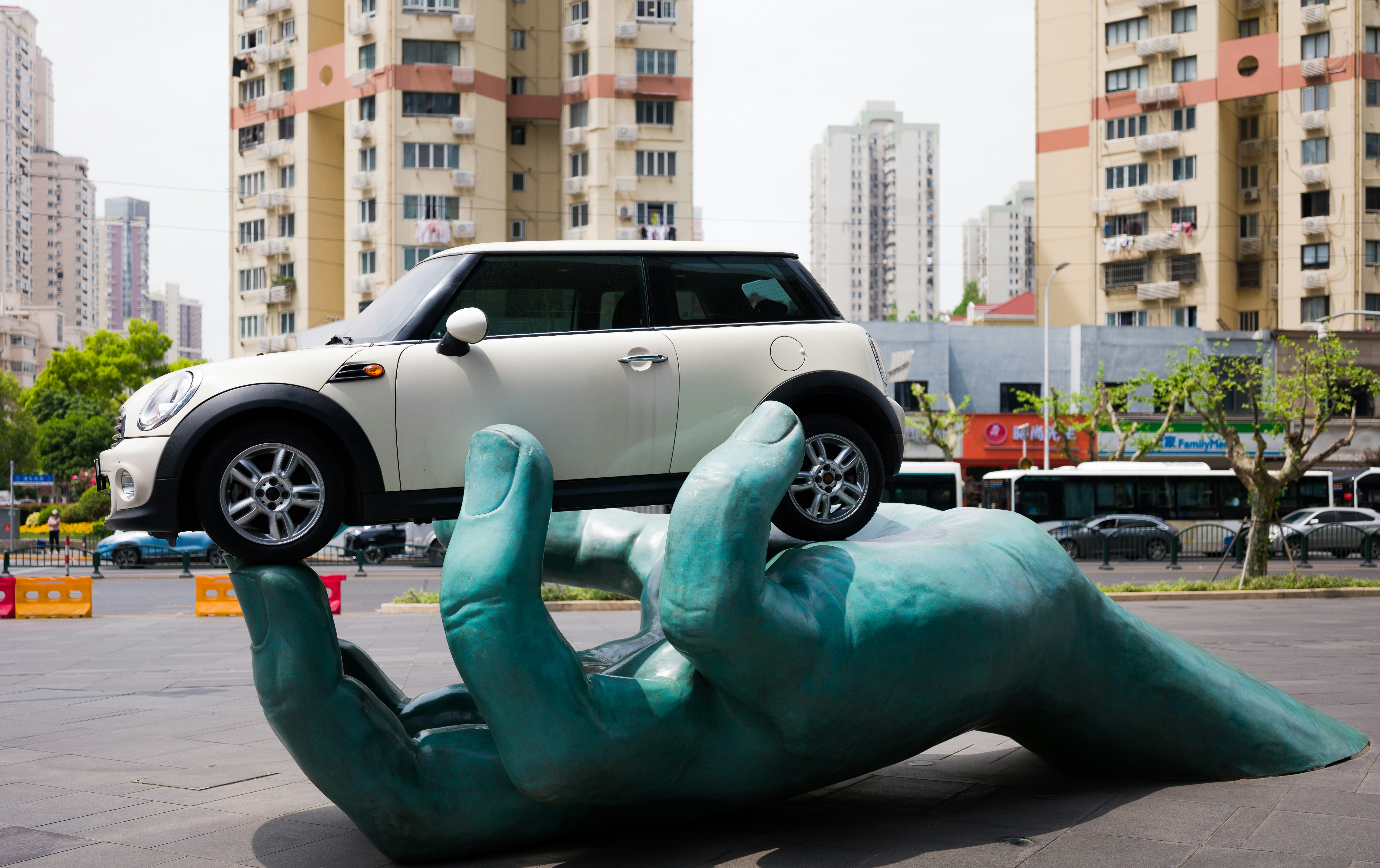 Urban Gravity: A Mini Cooper Balancing on a Turquoise Giant Hand