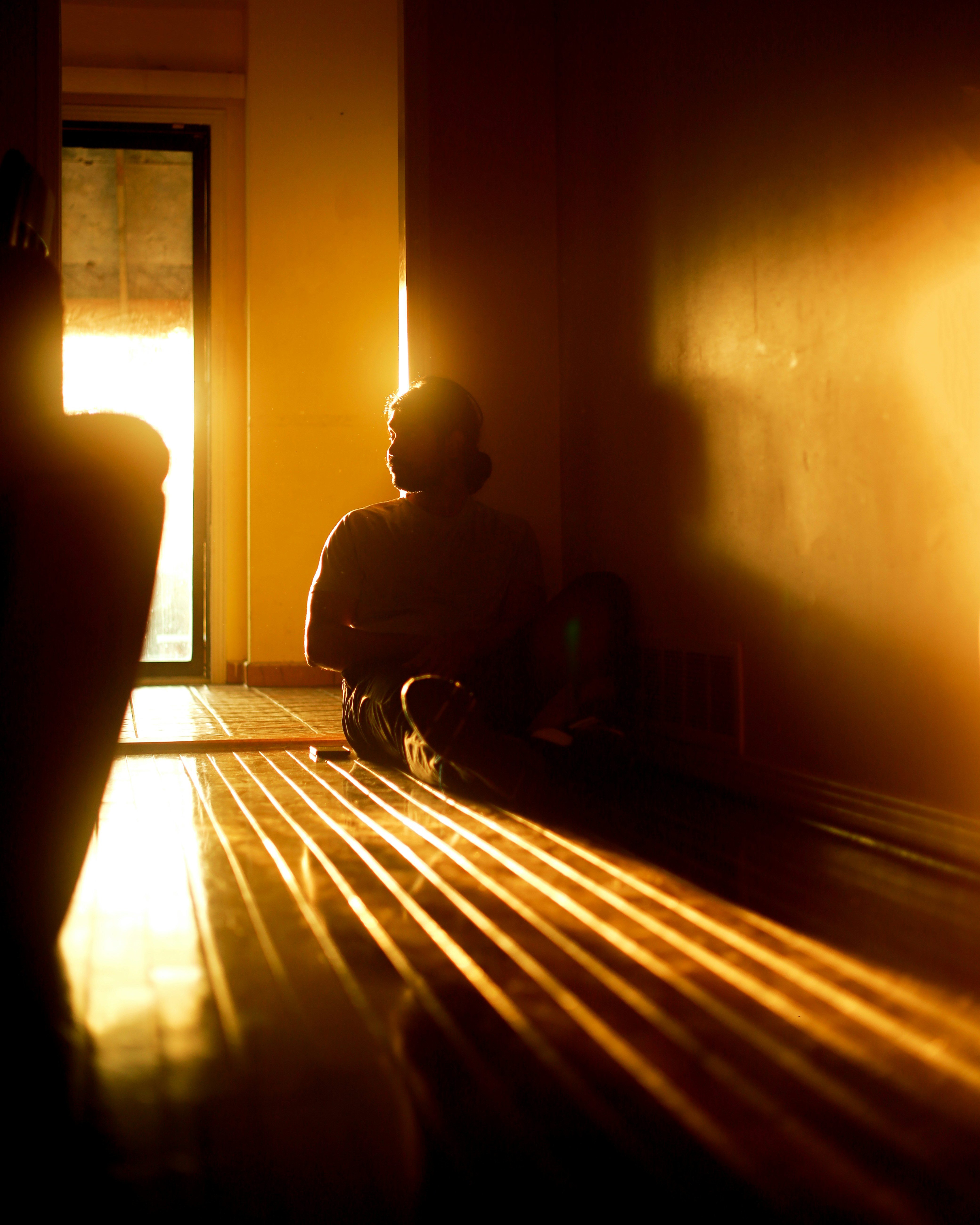 Amber Backlight: A Seated Silhouette in a Narrow Corridor