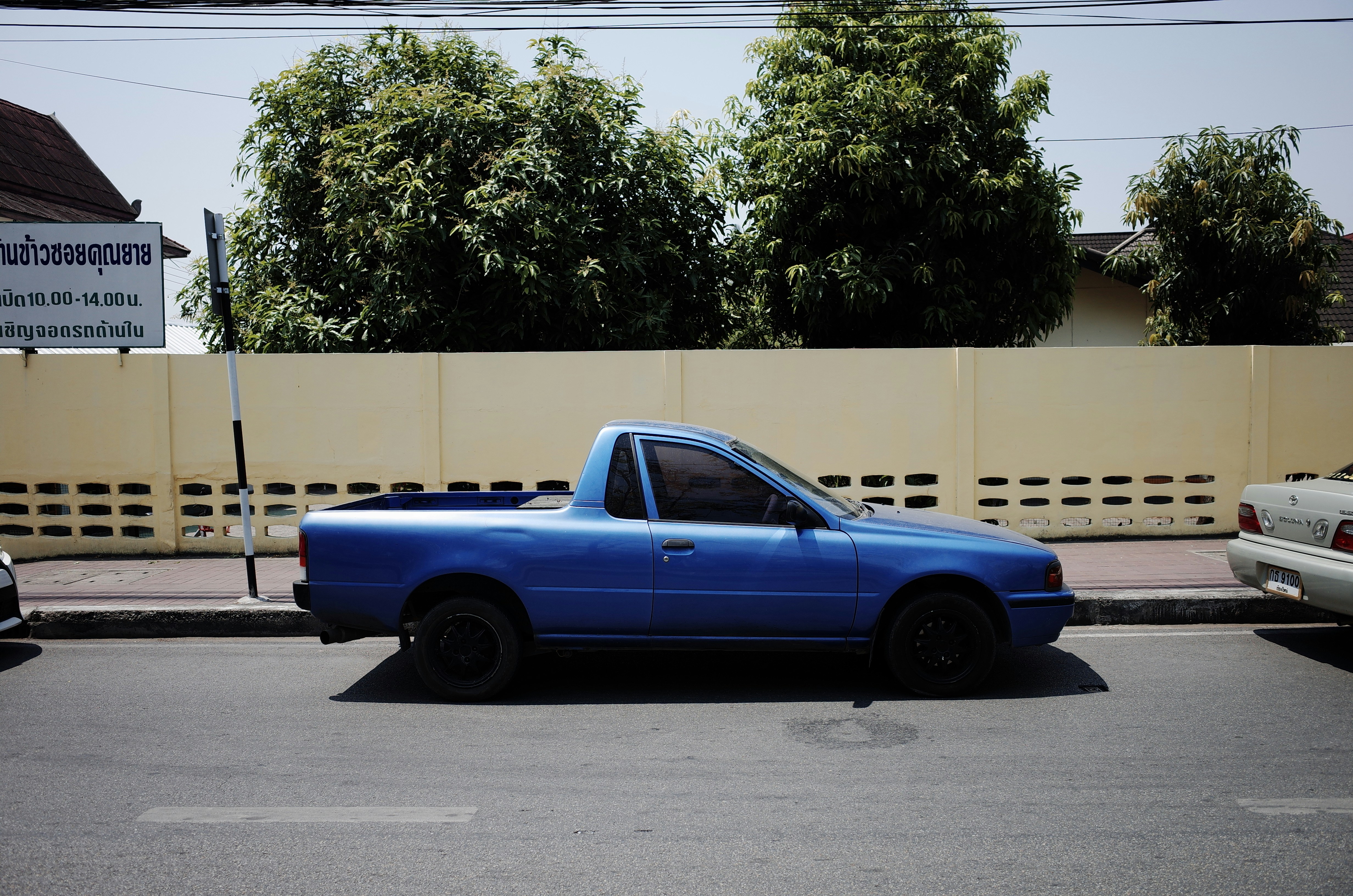 A blue pickup truck is parked on the street.
