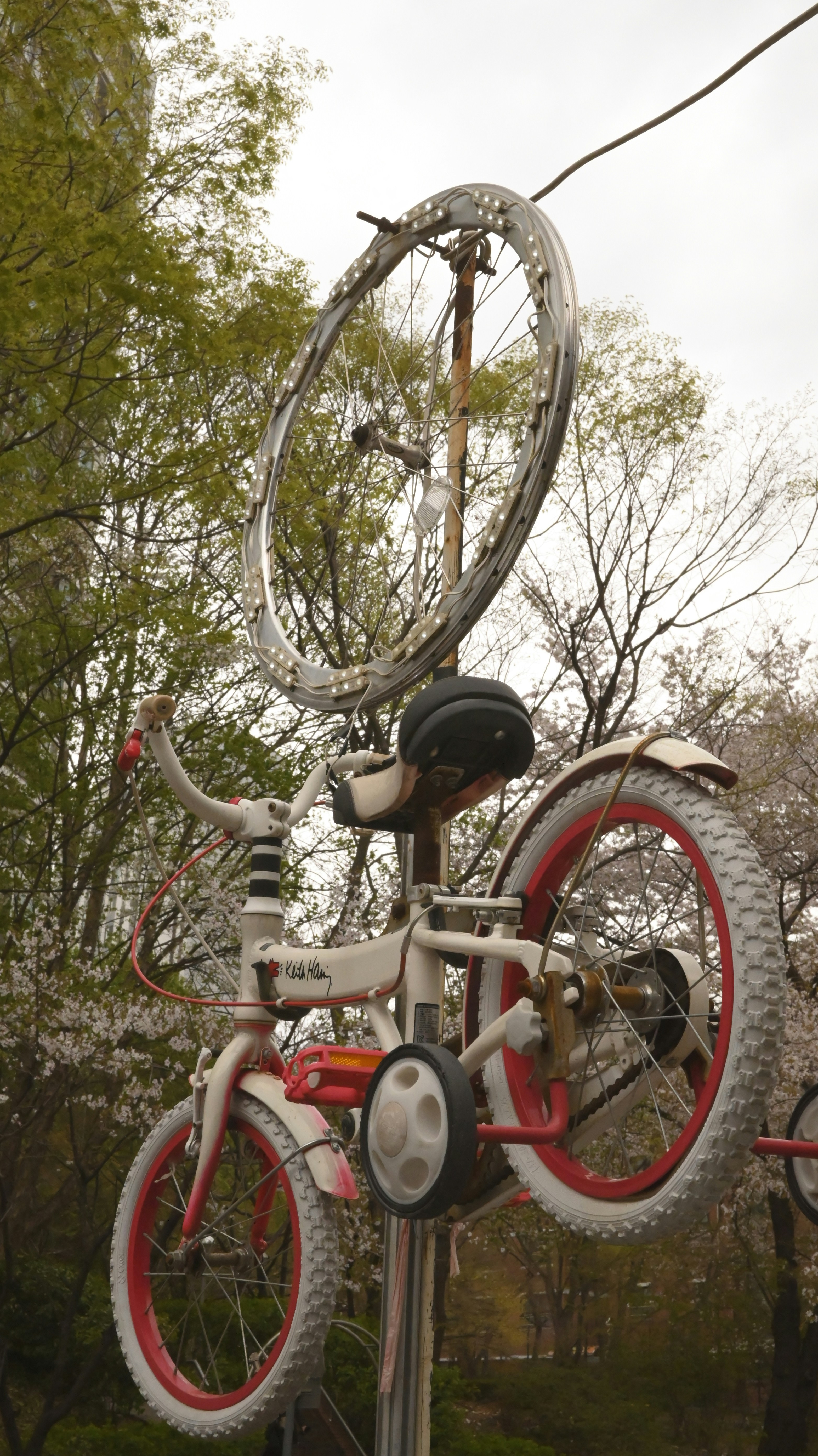 Orbiting Bicycle: A White Pedal Monument Reaching Through Spring Trees