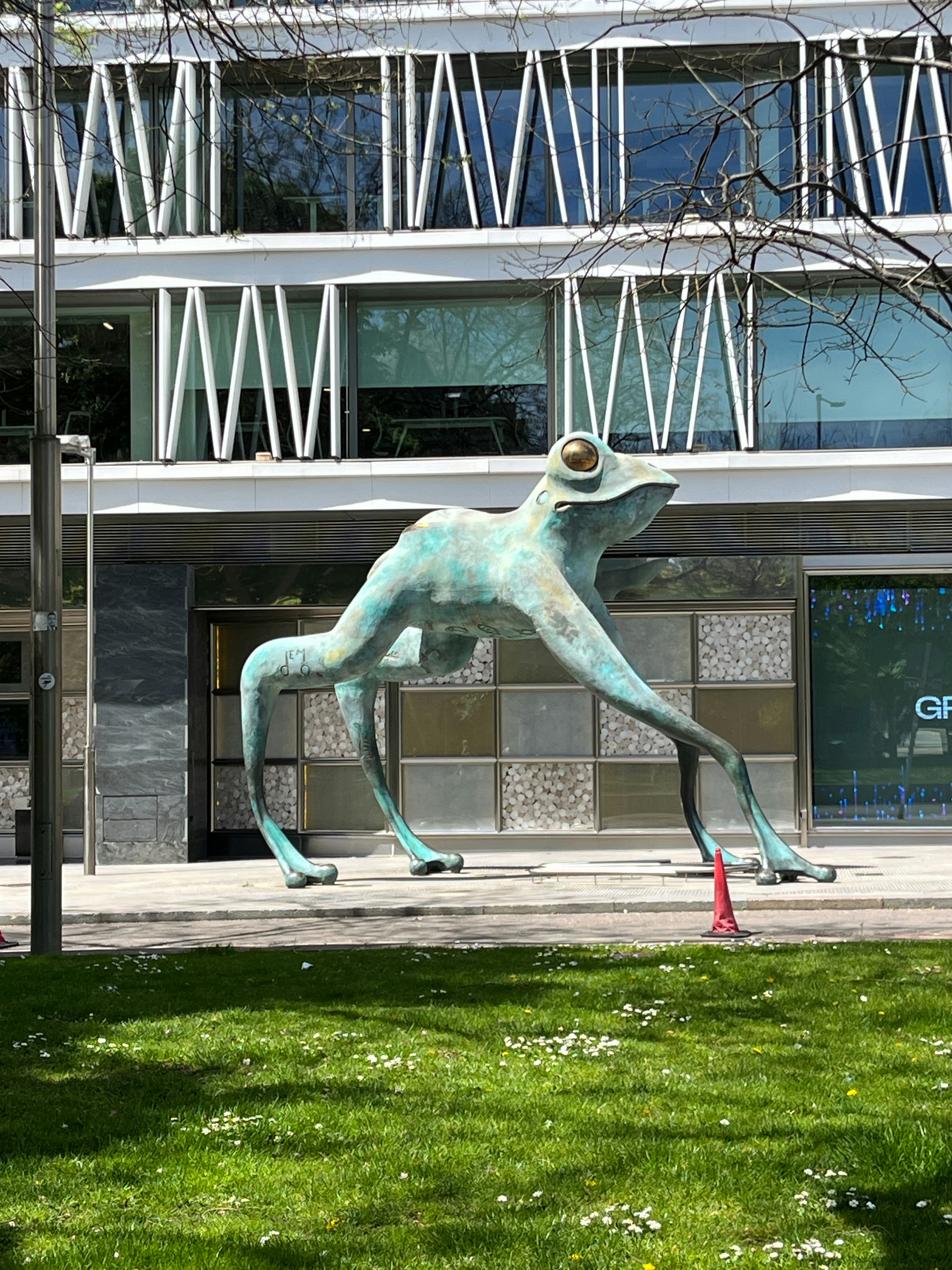 A bronze frog statue stands in front of a building. photo – Free Art ...