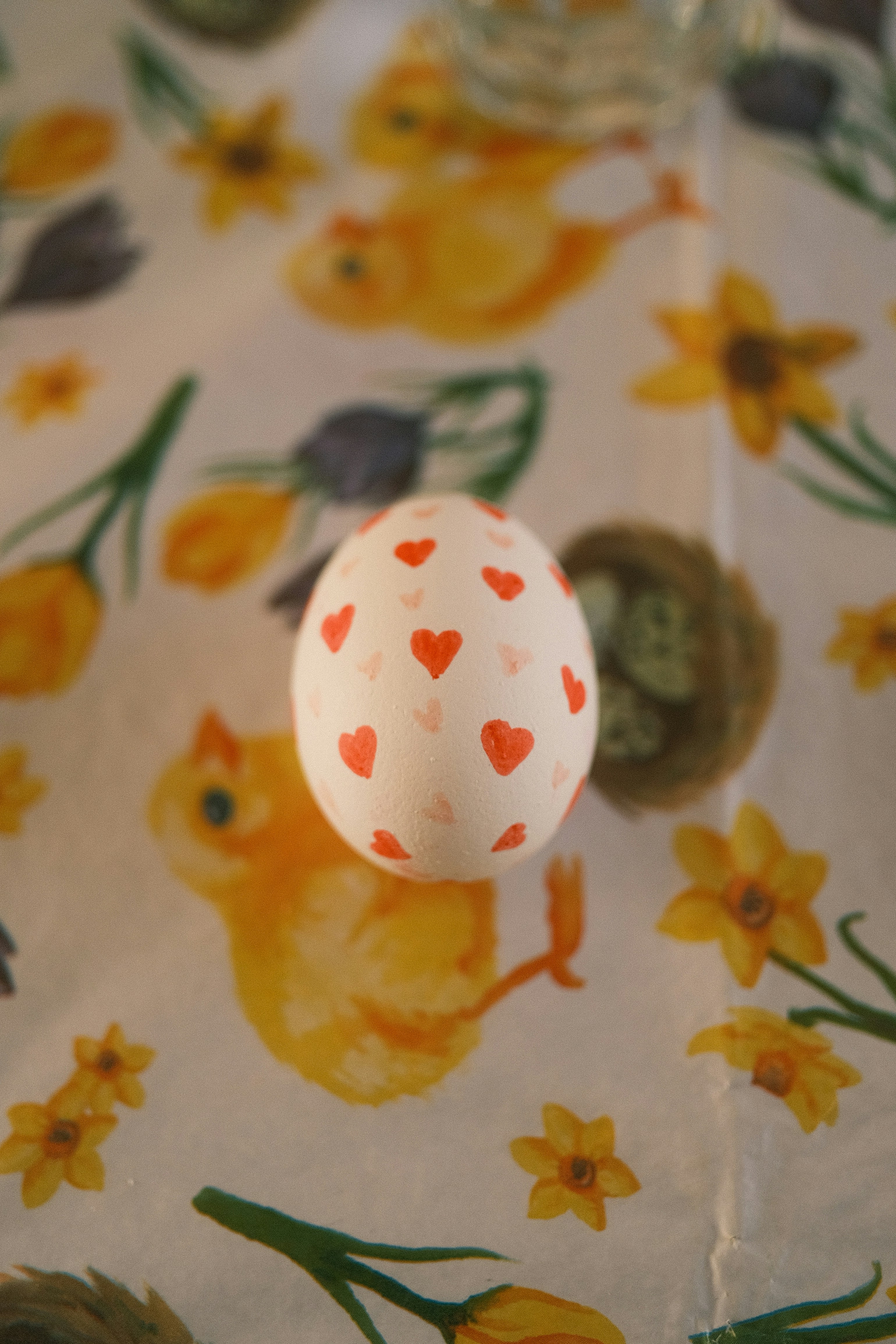 Centered Hearts: An Egg Adorned with Tiny Red Hearts on Floral Linen