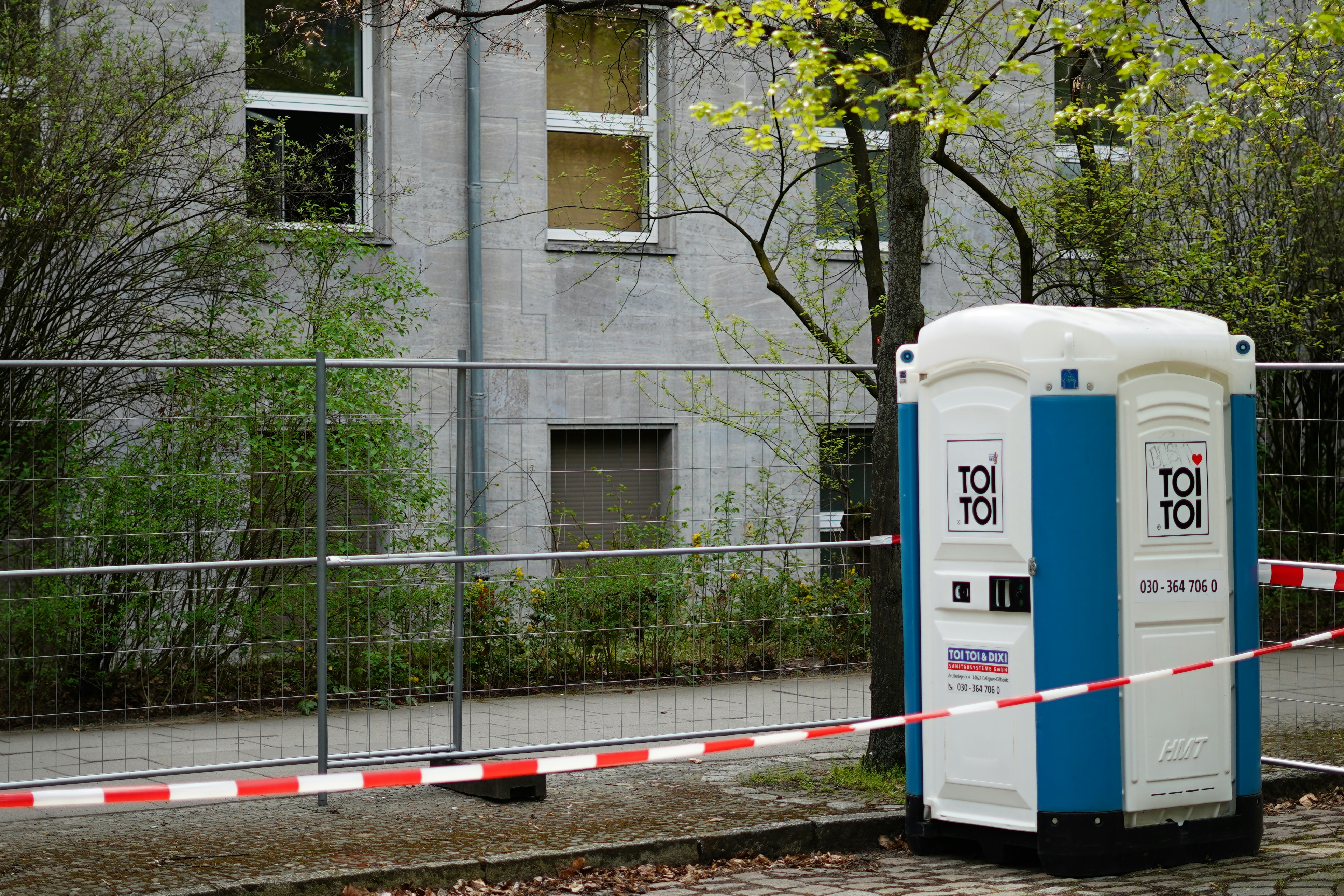 Blue Porta-Potty Duo Framed by Red Tape in an Urban Yard