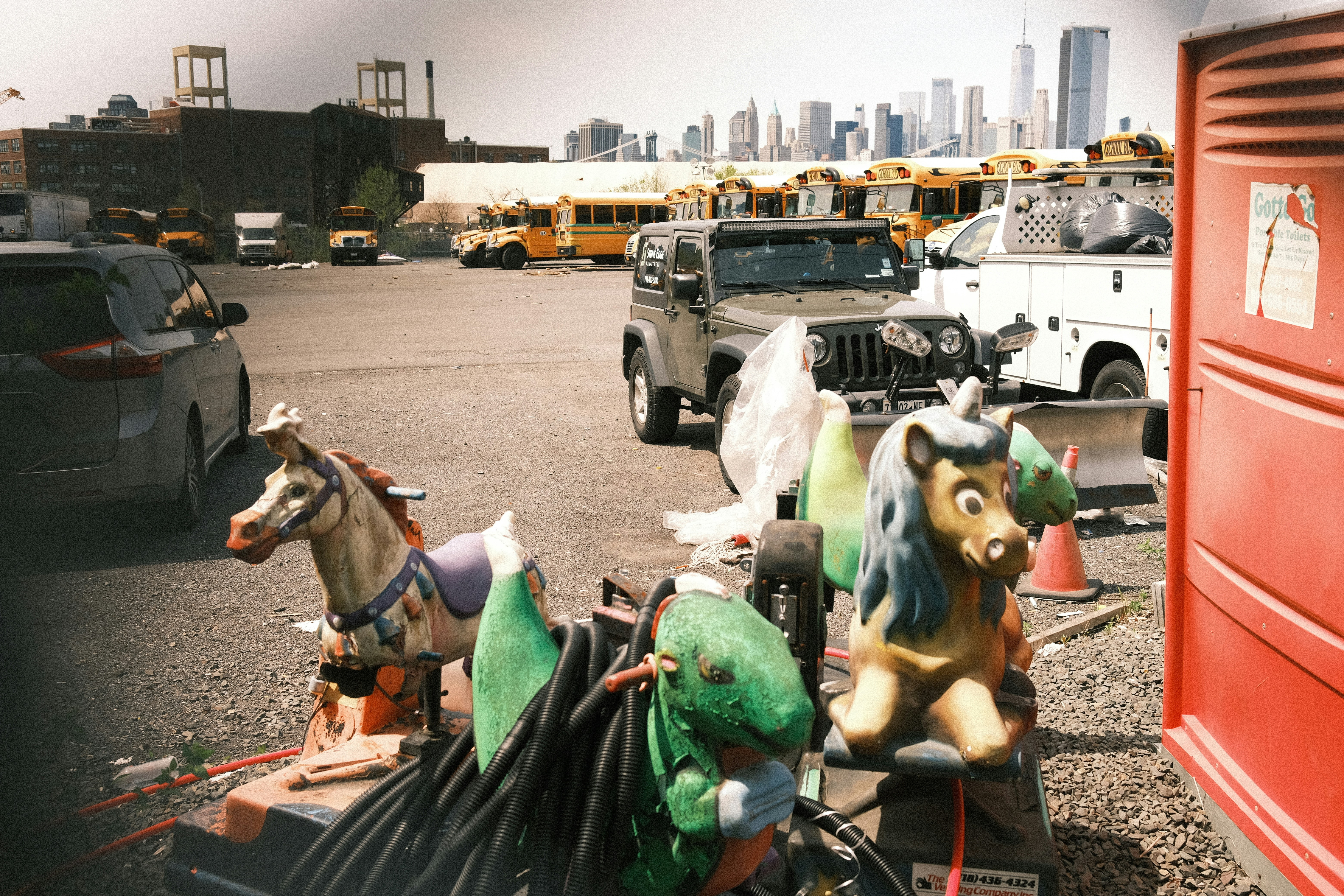 Abandoned playground toys sit amidst a parking lot.