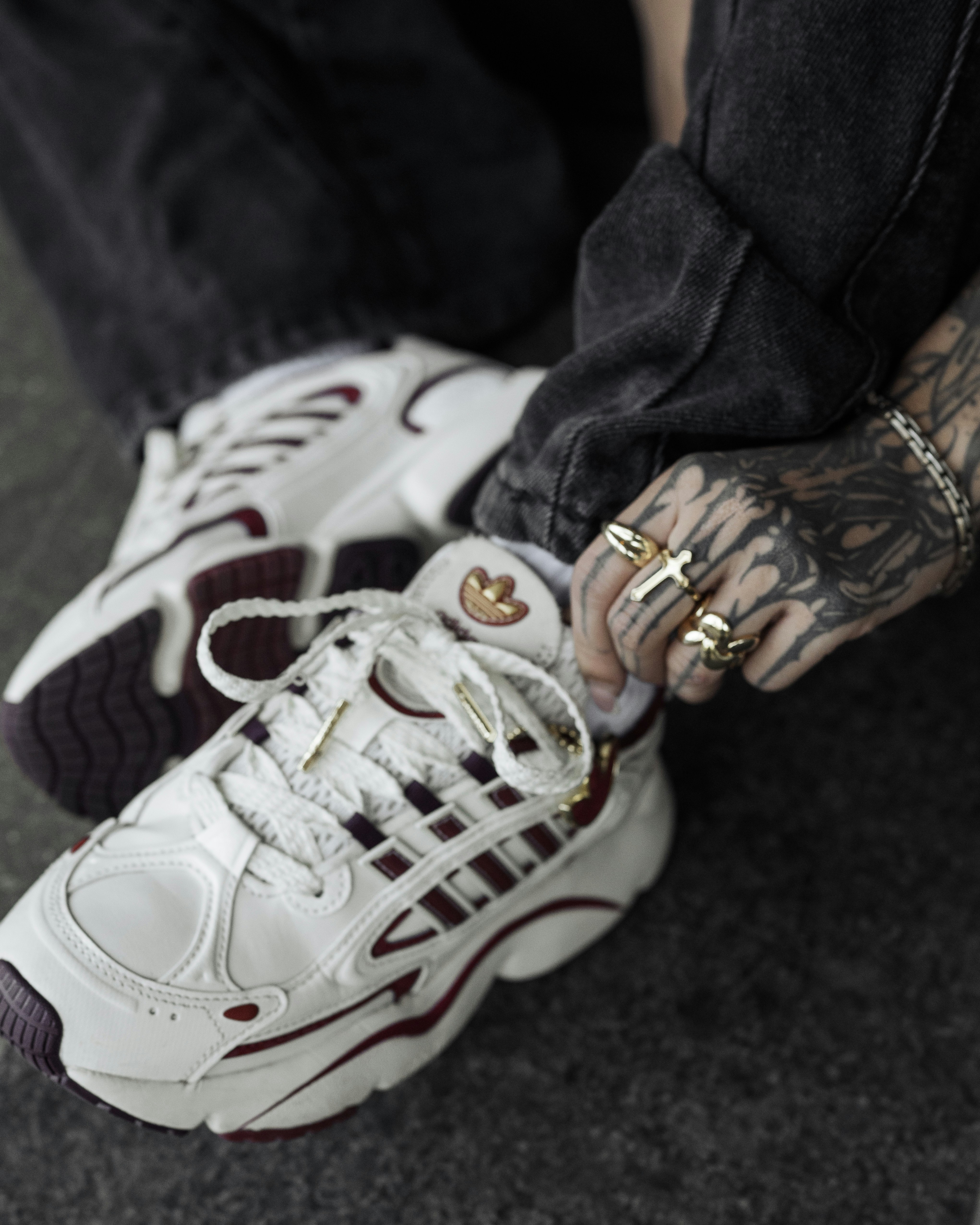 Someone is lacing up a white and maroon sneaker. photo – Free Human ...