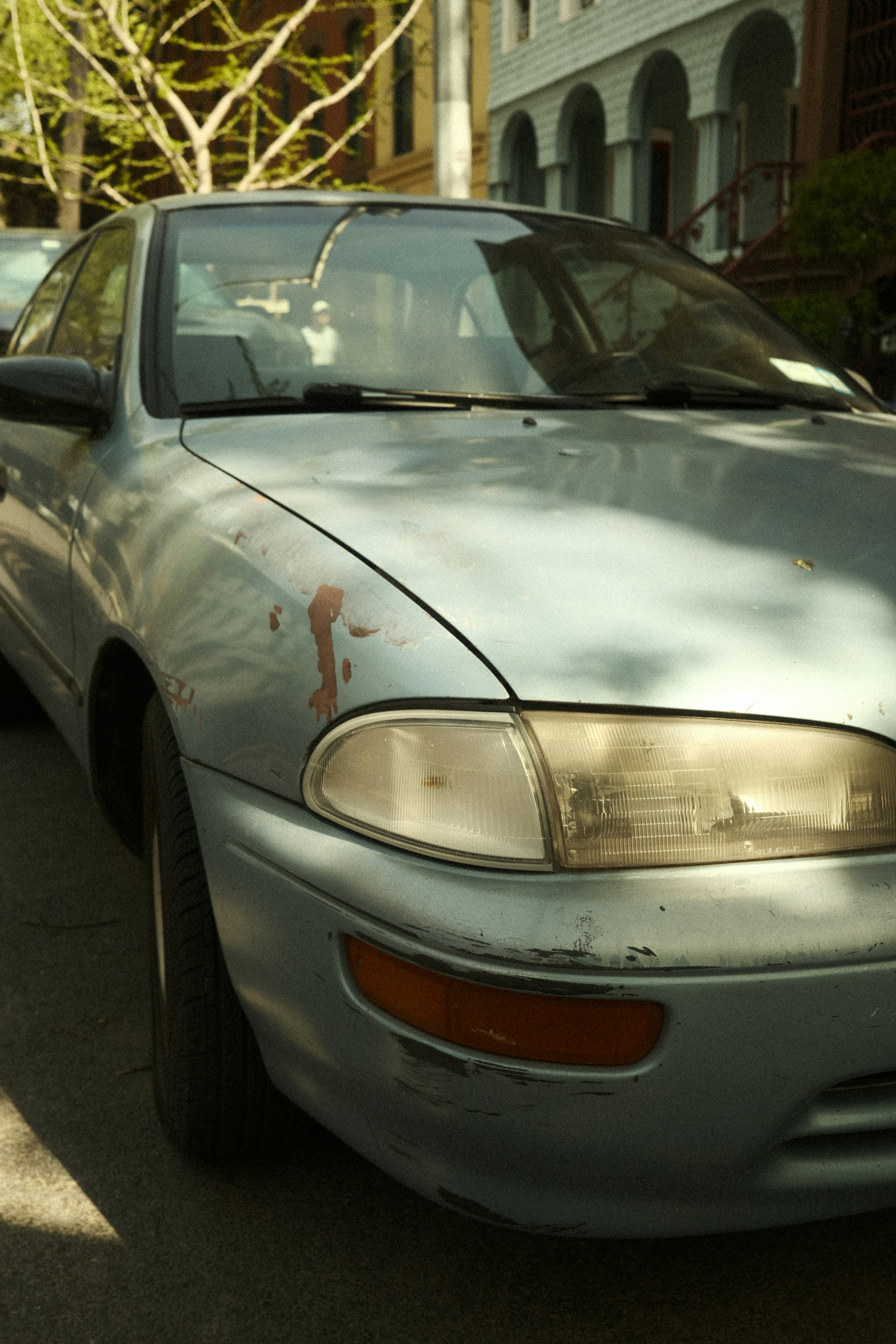 A weathered blue car parked on a street.