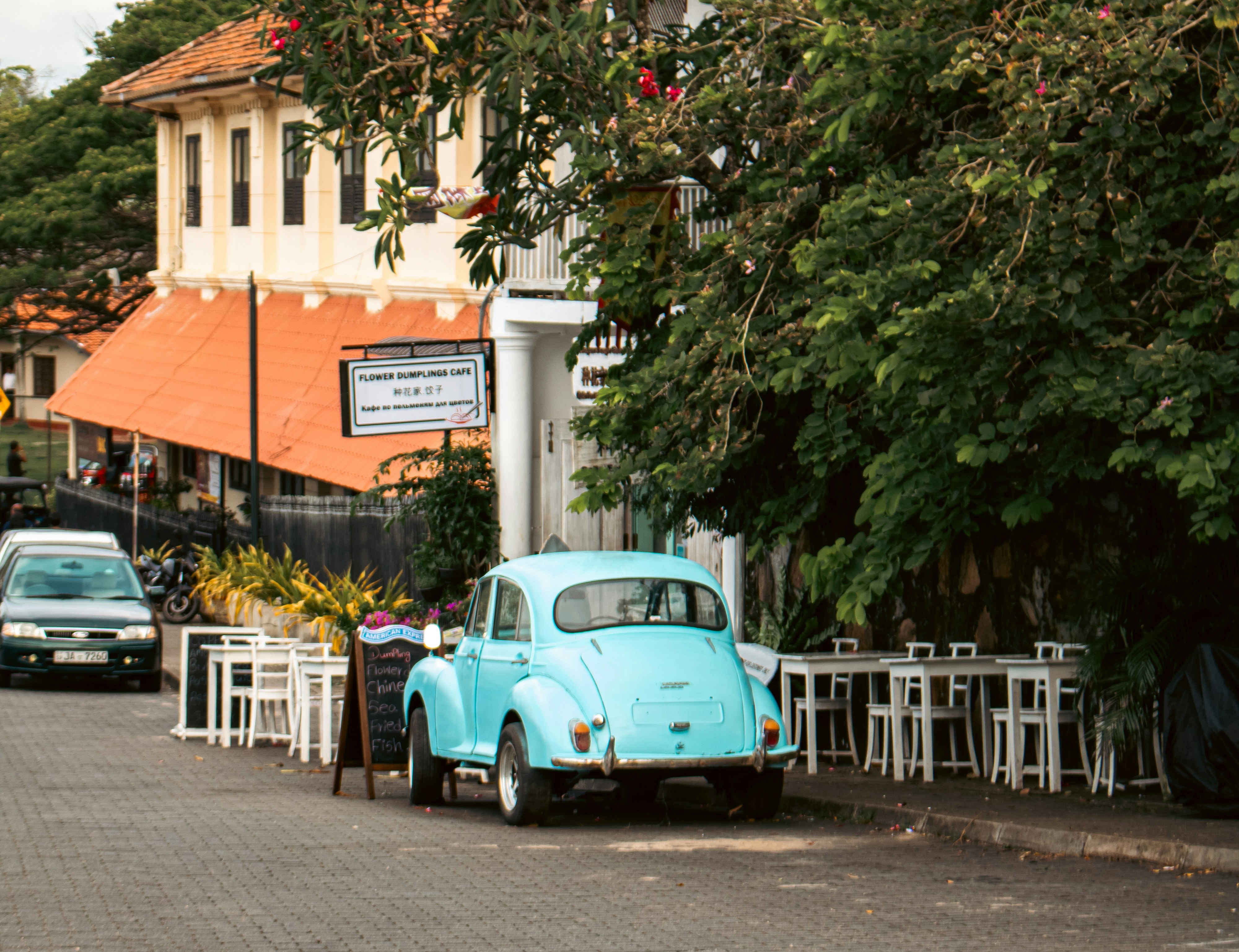 Turquoise vintage car under leafy storefront canopy