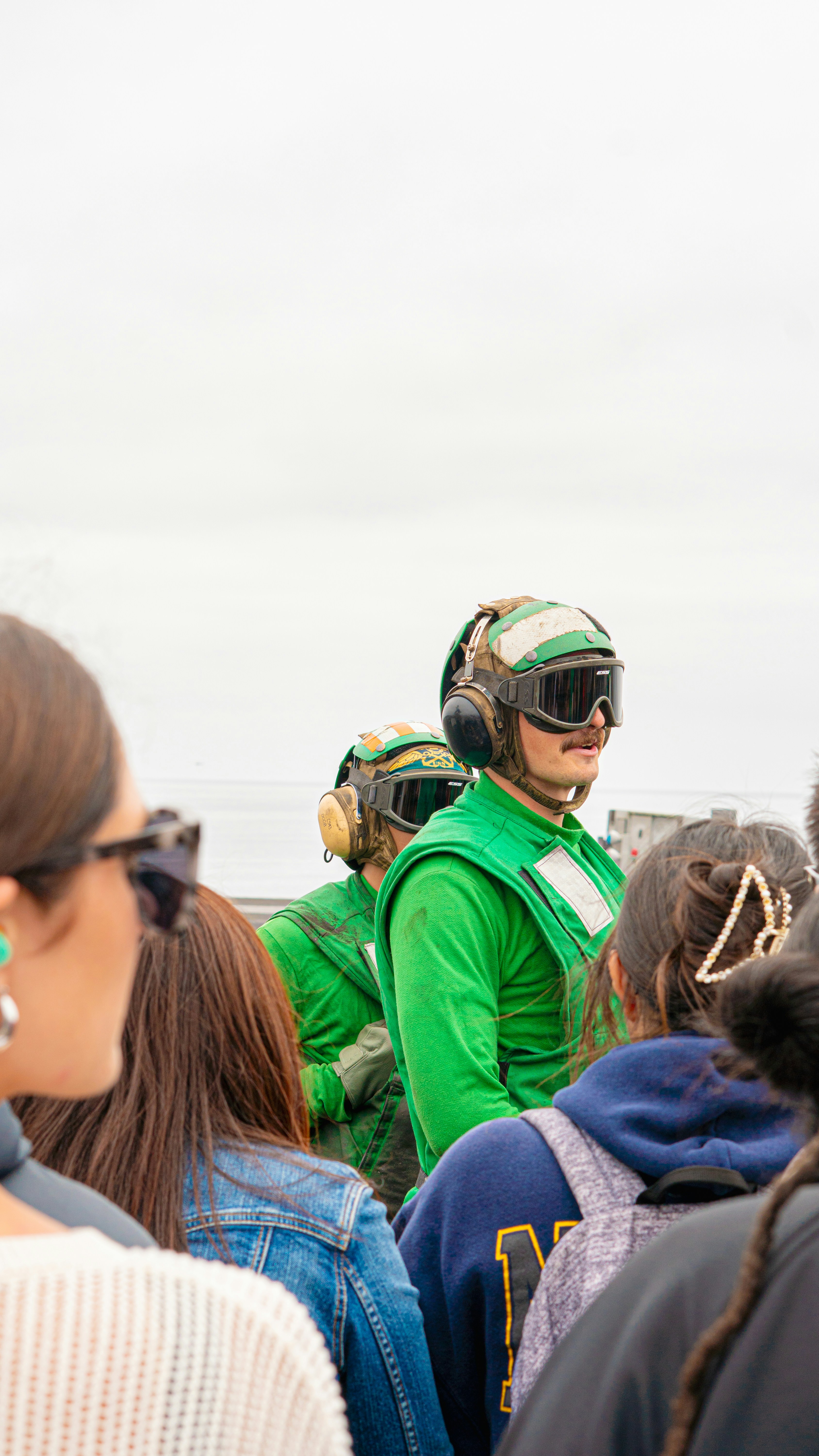 Green Flight: A Helmeted Figure Amid a Crowd of Onlookers