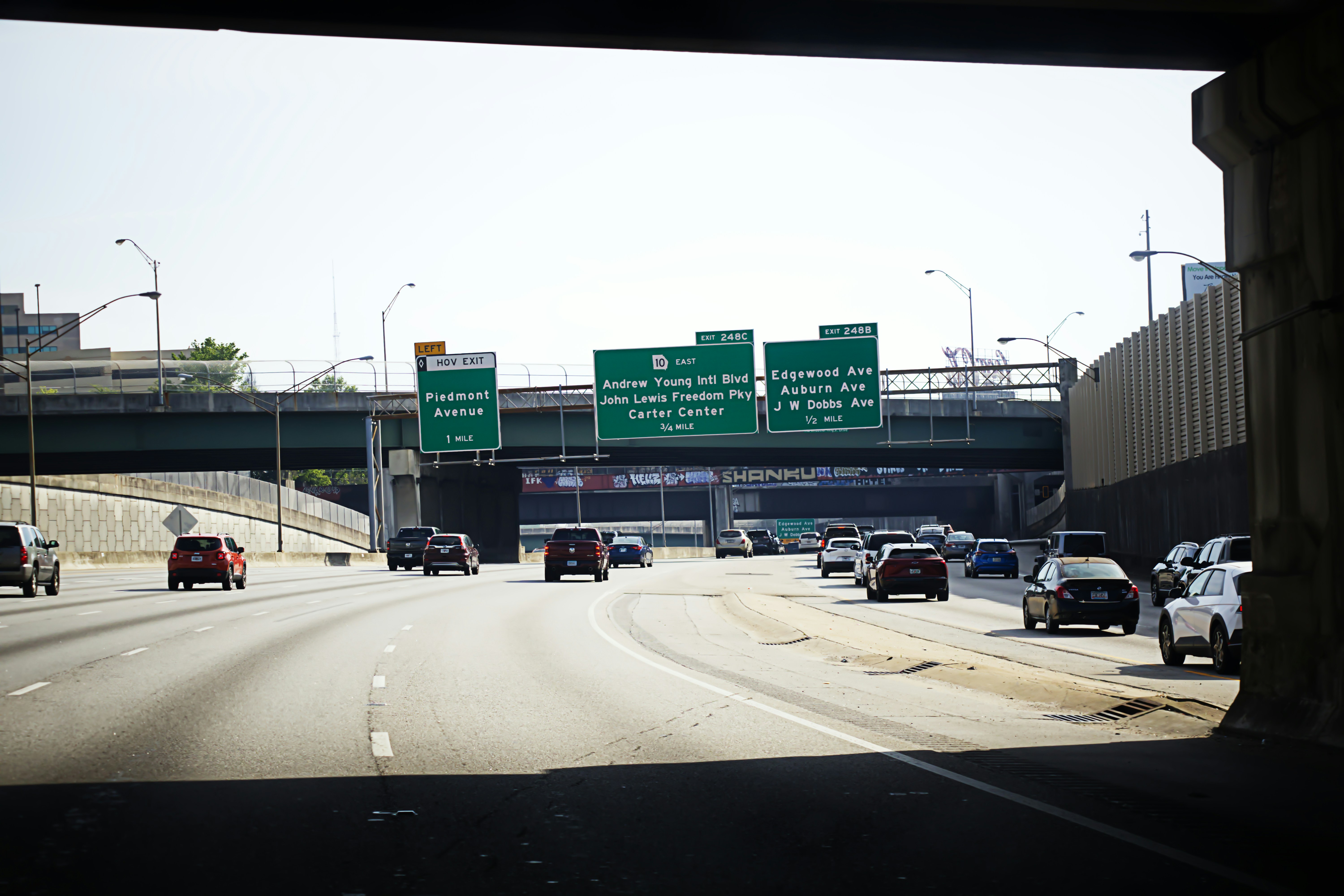 Green Signway Beneath City Arches: Morning Traffic on a Sunlit Freeway