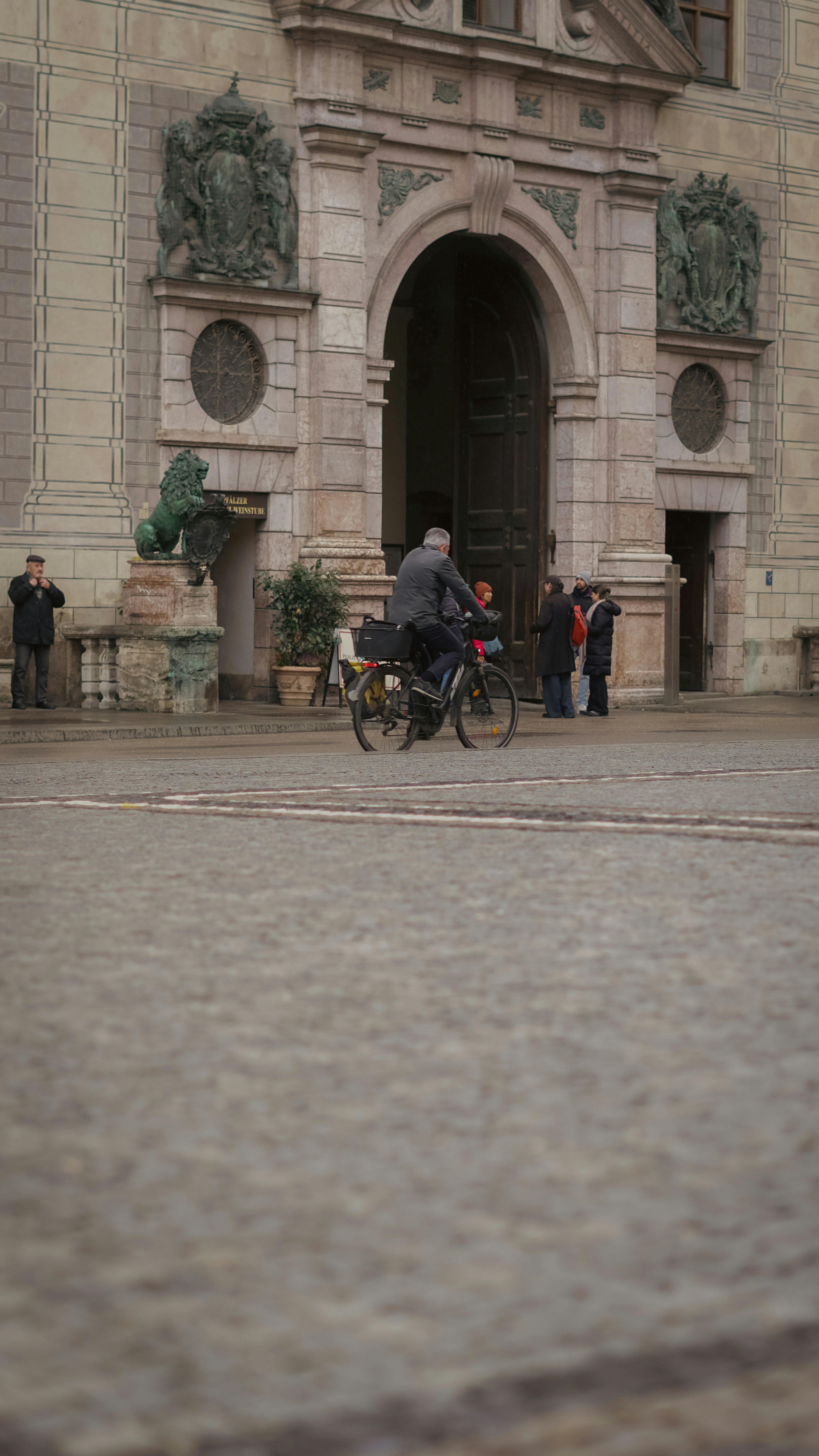 A person rides a bicycle near a building entrance. photo – Free ...