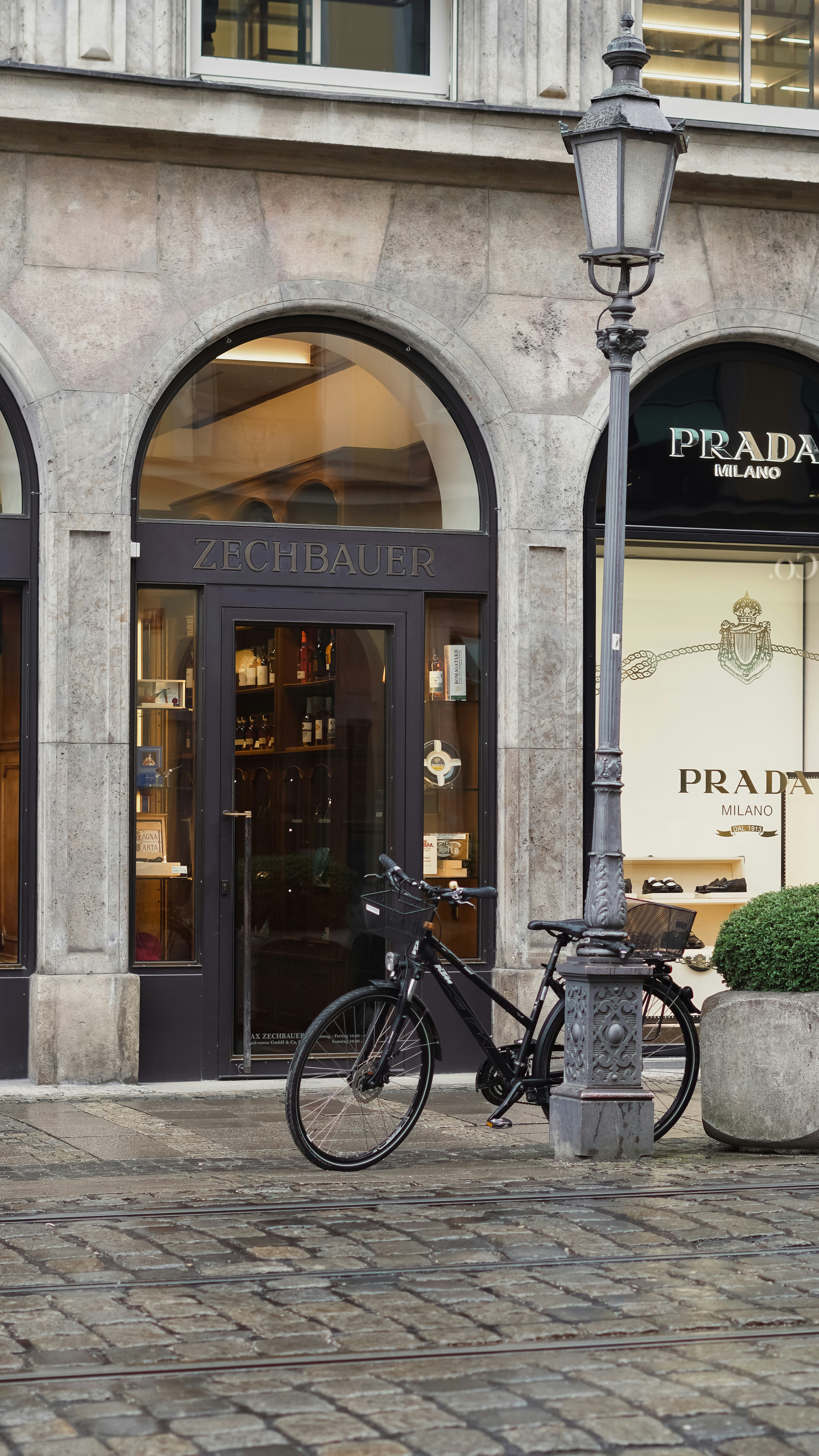 Cycling Streetfront: A Noir Bicycle at a Prada-Lit Facade