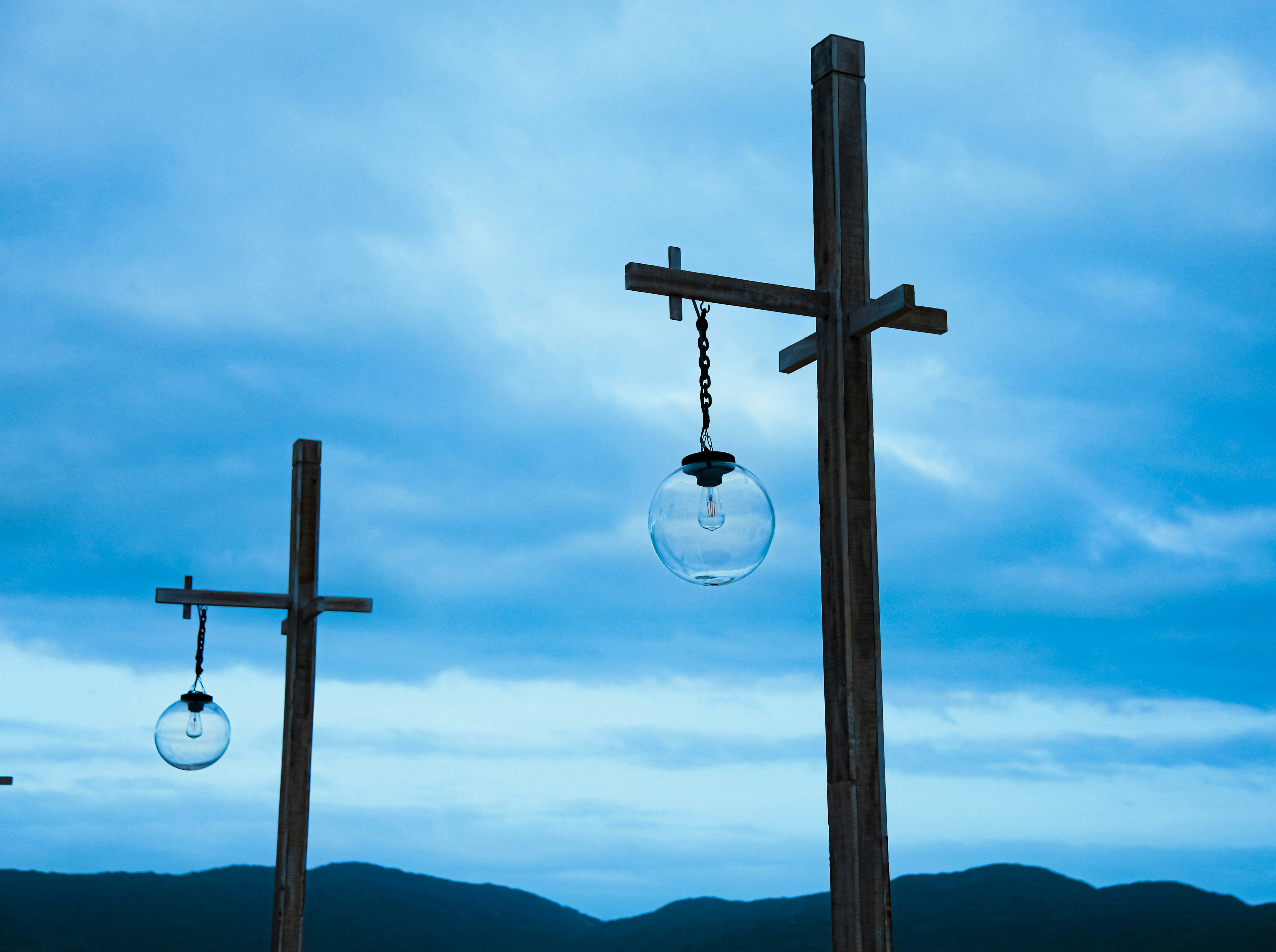 Lanterns on Weathered Crosses Under a Quiet Blue Horizon